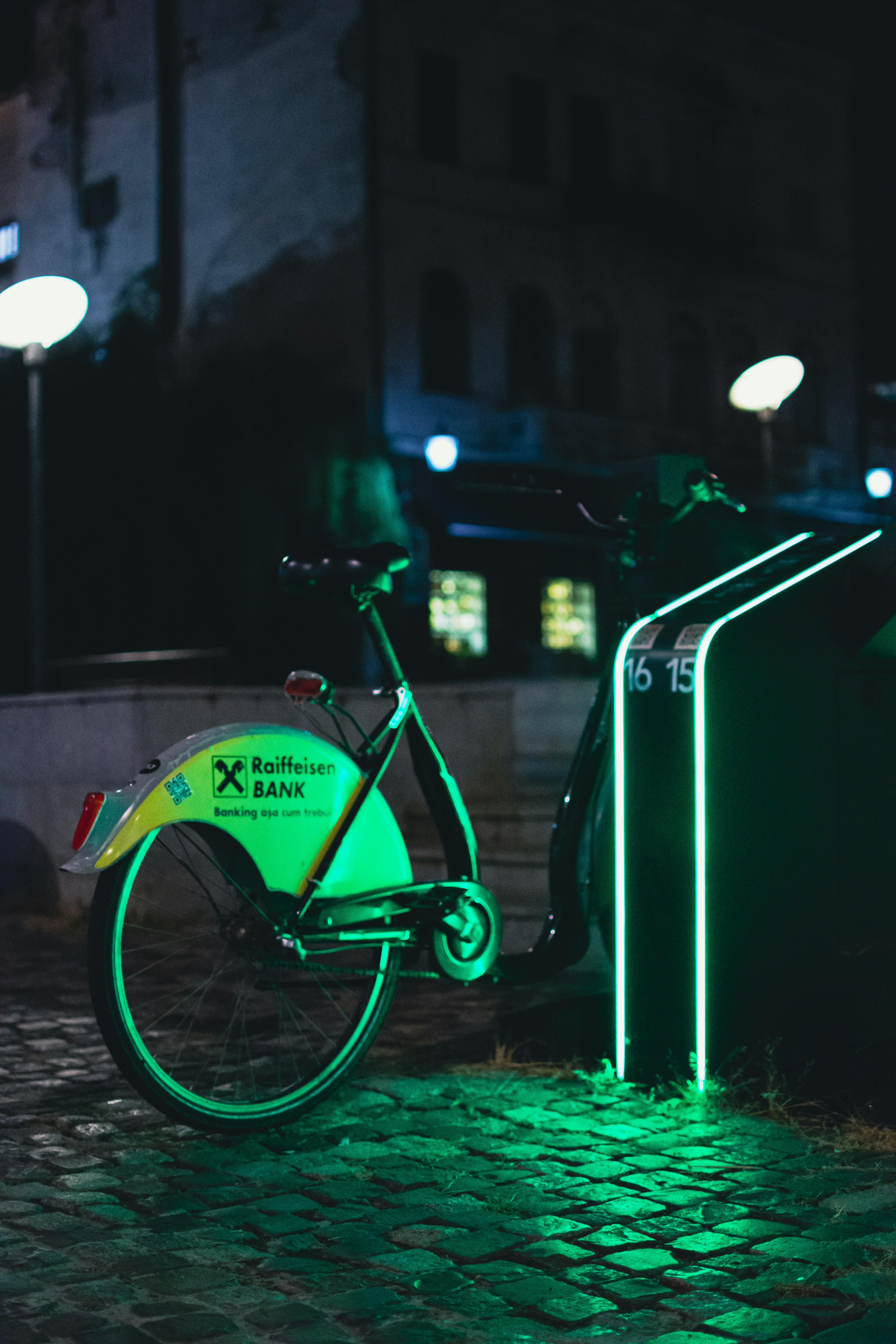 Green city bike parked beside green metal post during night time photo ...