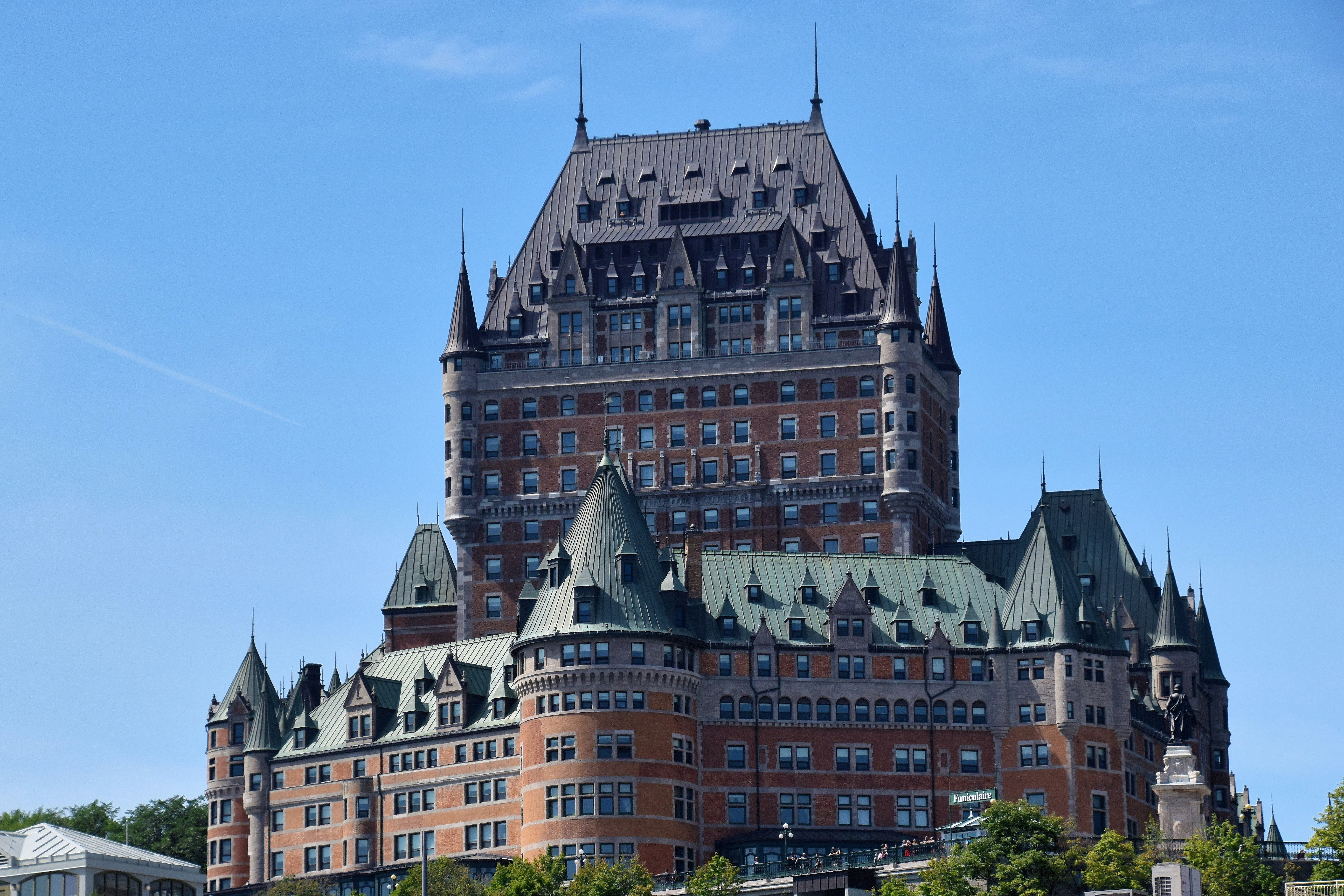 Historic château with green spires and ornate architecture under clear blue sky.