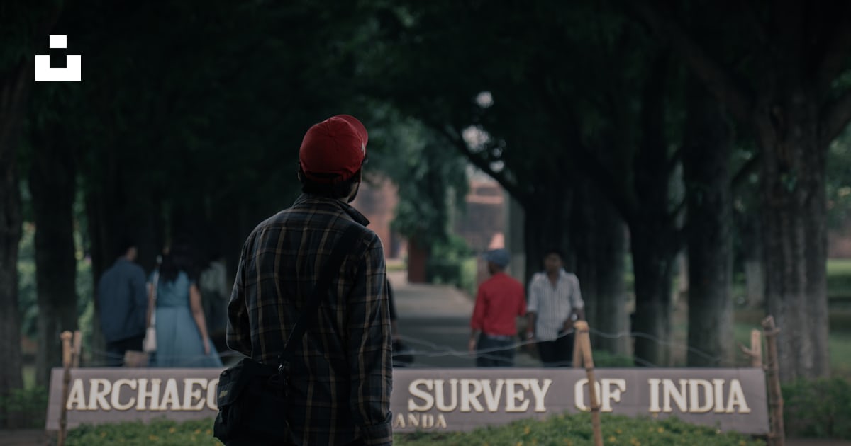 Man In Black And White Plaid Dress Shirt And Red Cap Standing On Road