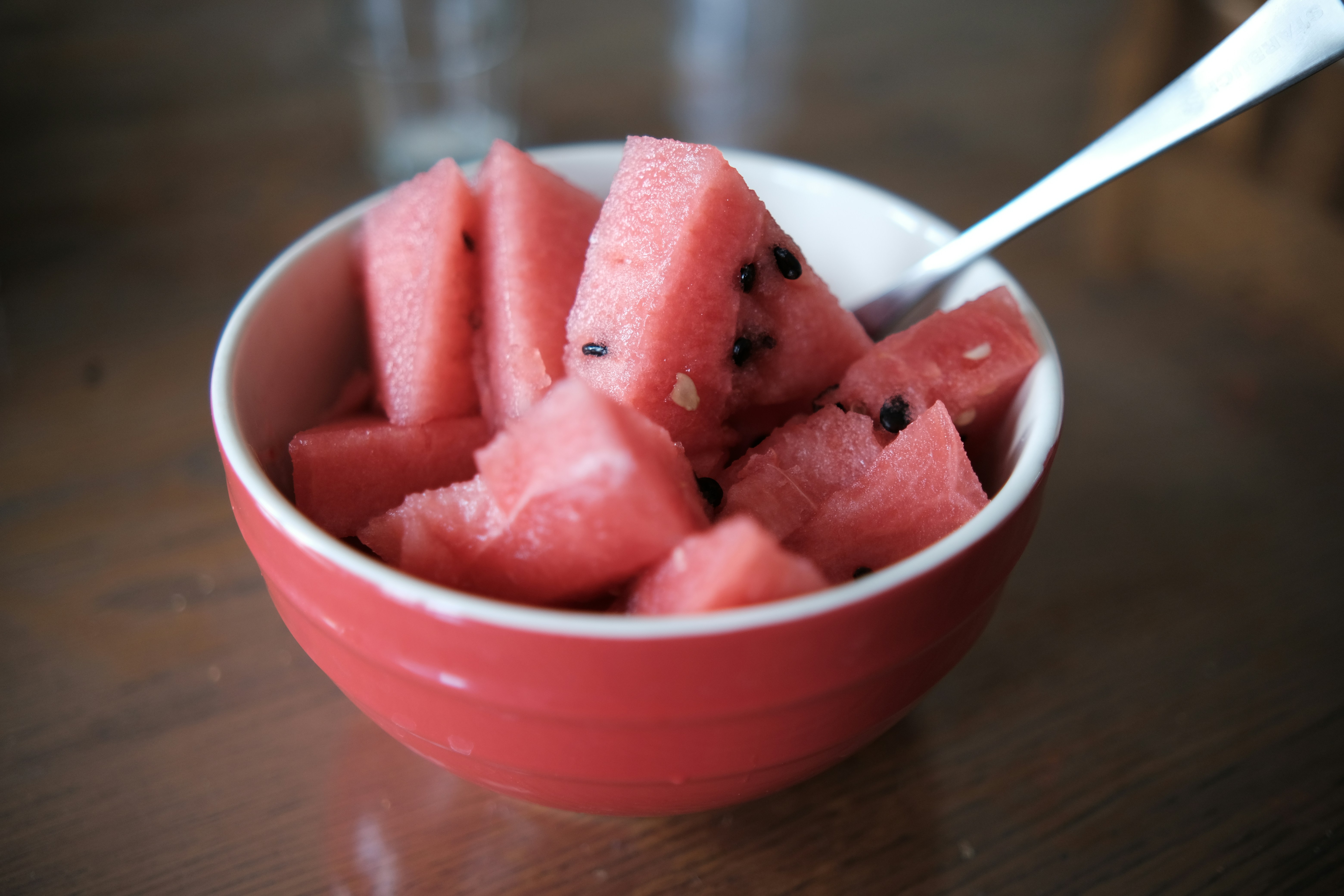 Freshly cut watermelon cubes in a vibrant red bowl, showcasing the juicy texture and seeds of the fruit.