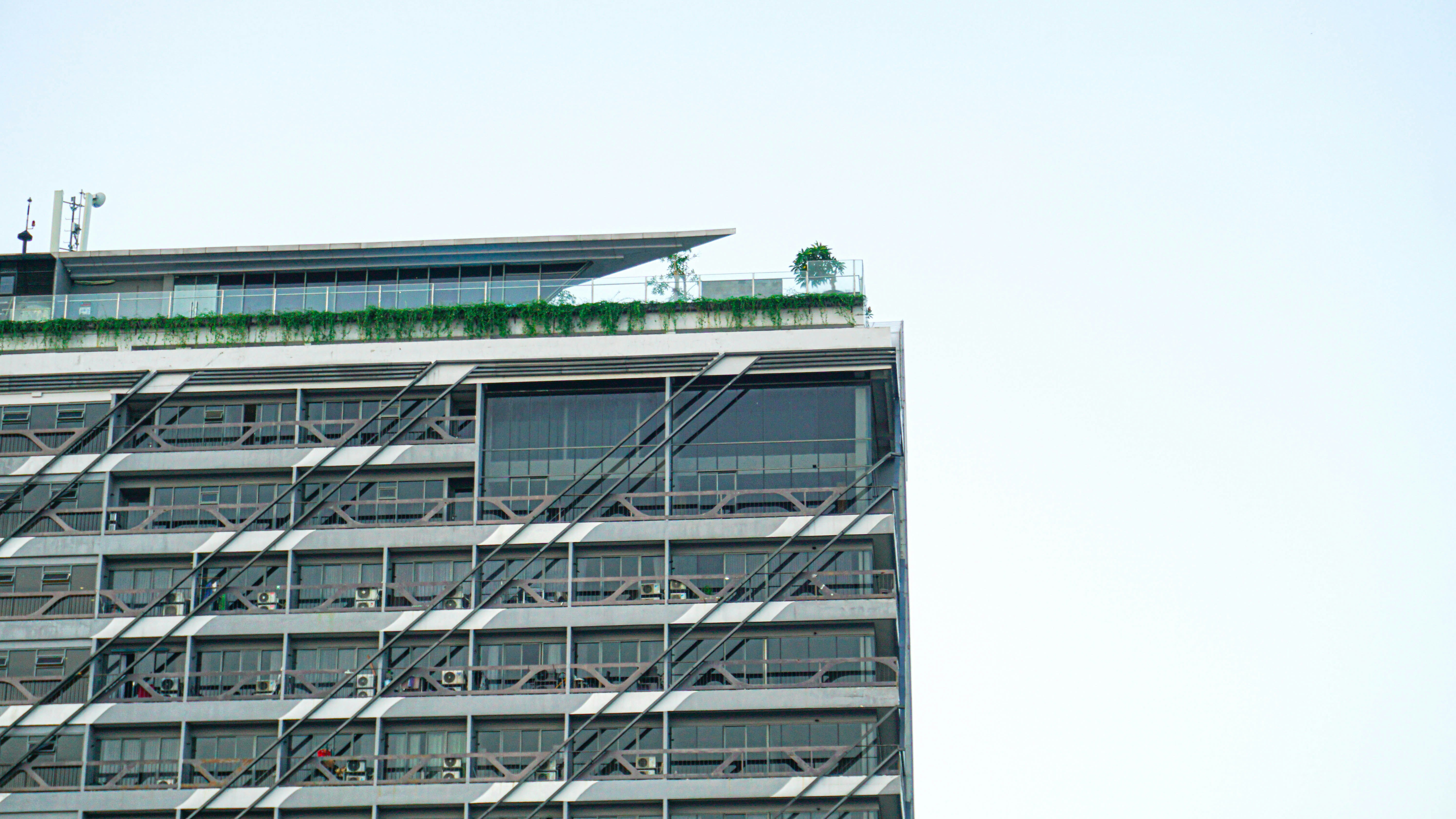 Modern building showcasing a rooftop garden with greenery and architectural lines, highlighting urban design. 