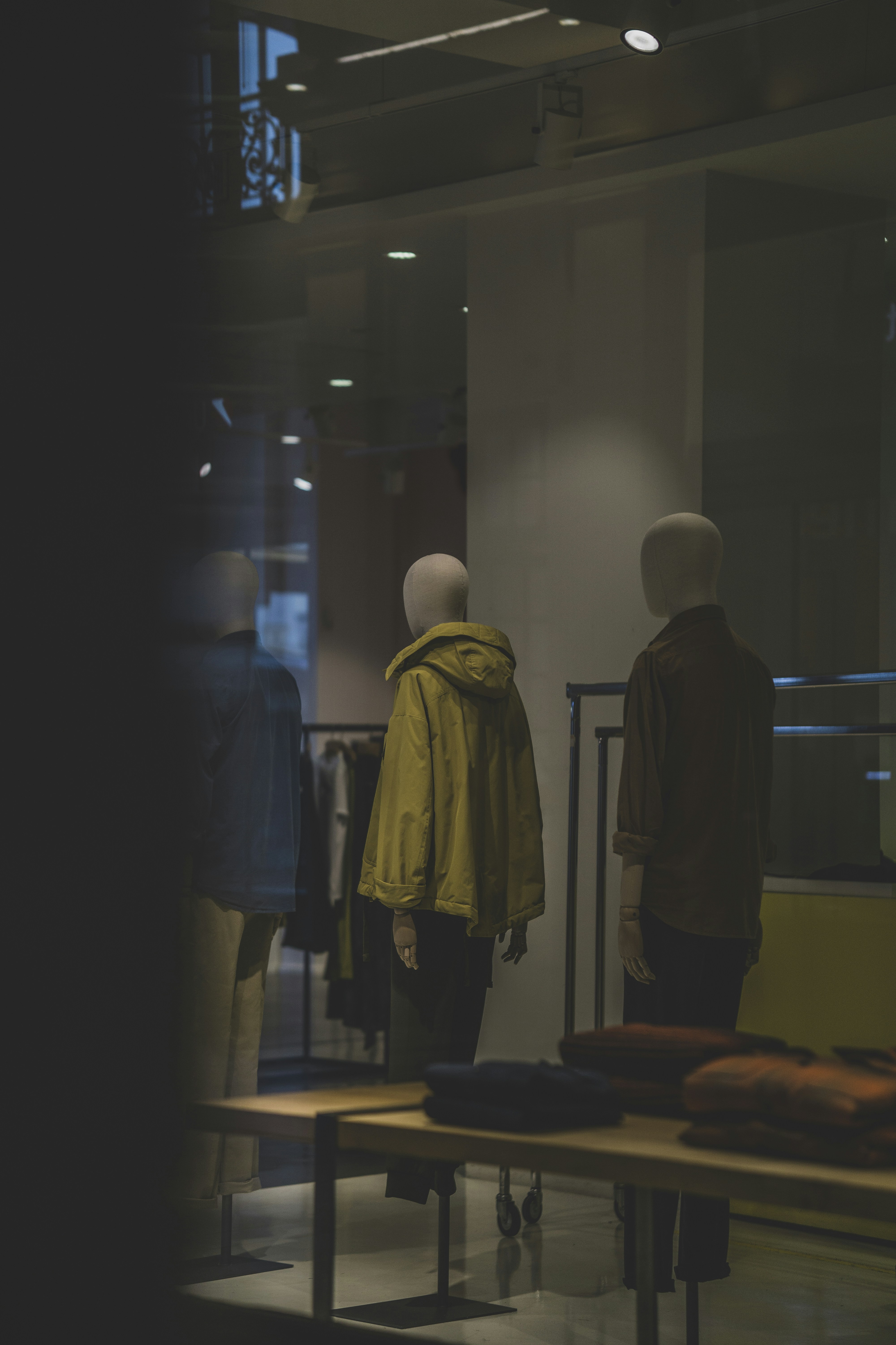 Mannequins dressed in casual attire stand in a modern retail space, showcasing fashion trends in a minimalist setting.
