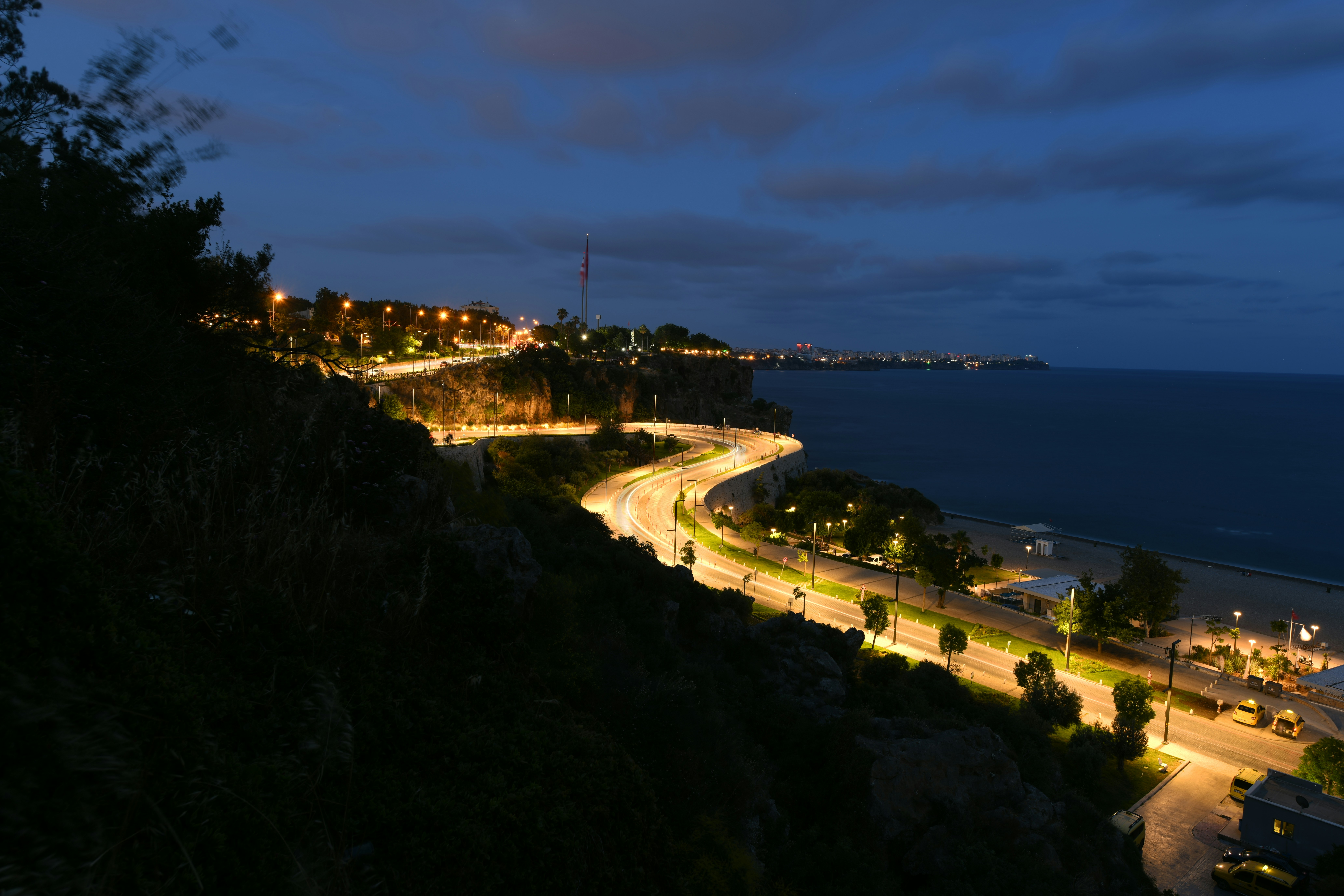 Illuminated coastal road winding along the seaside under a twilight sky.