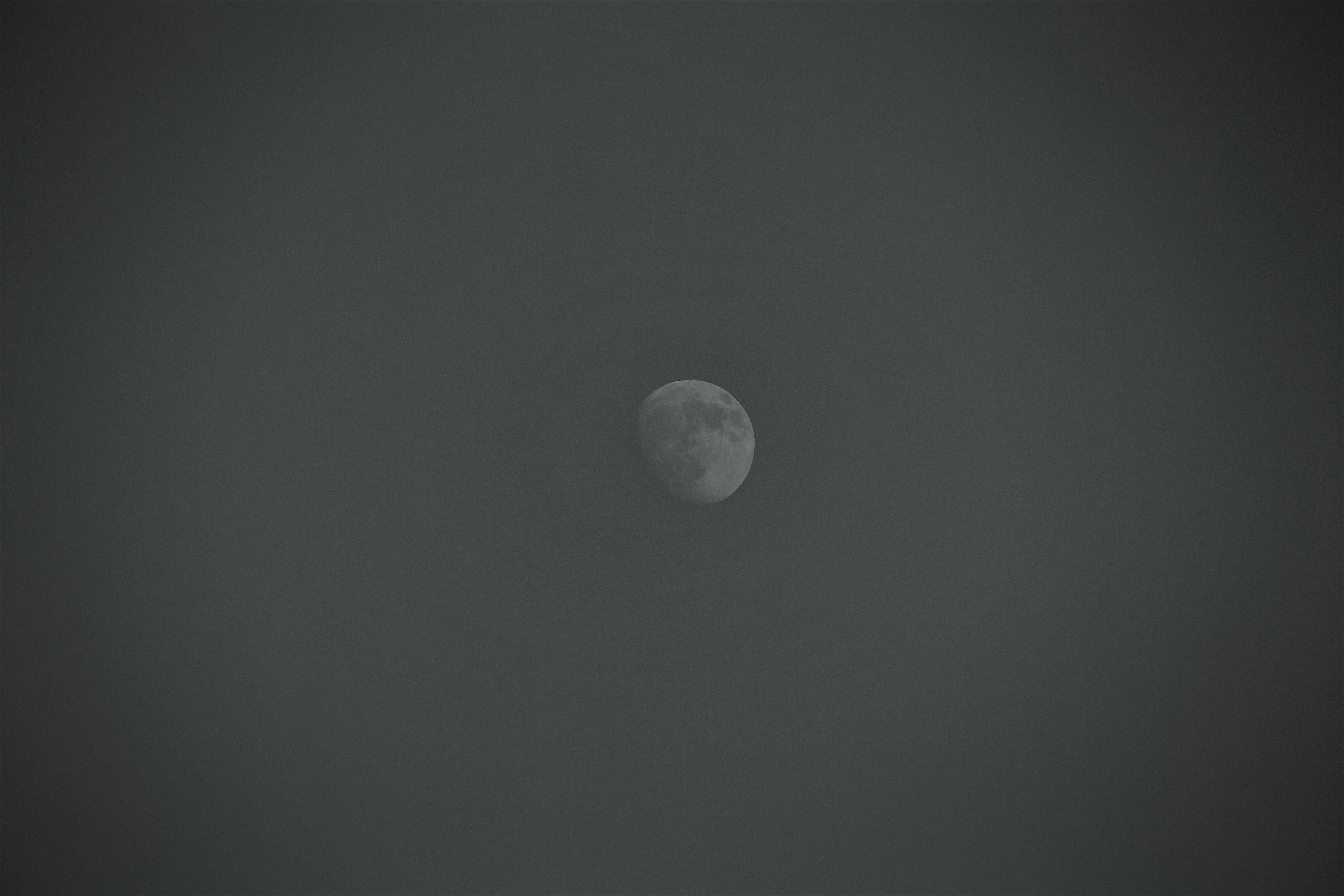 Waxing moon illuminated against a subtle, dark sky, creating a tranquil celestial scene.