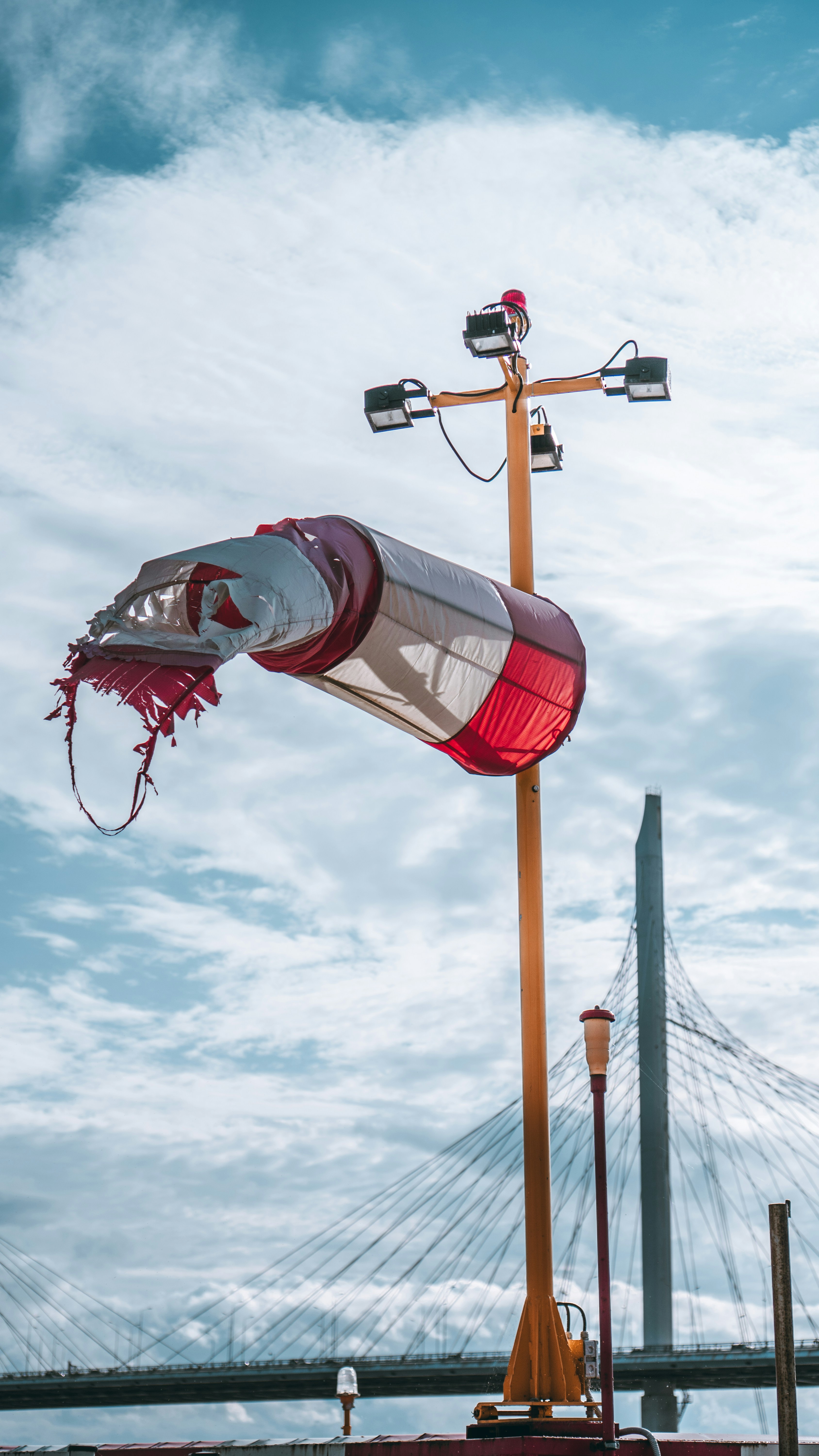 Pole-Top Gust: A Windsock Unfurls Against a Cable-Stayed Horizon