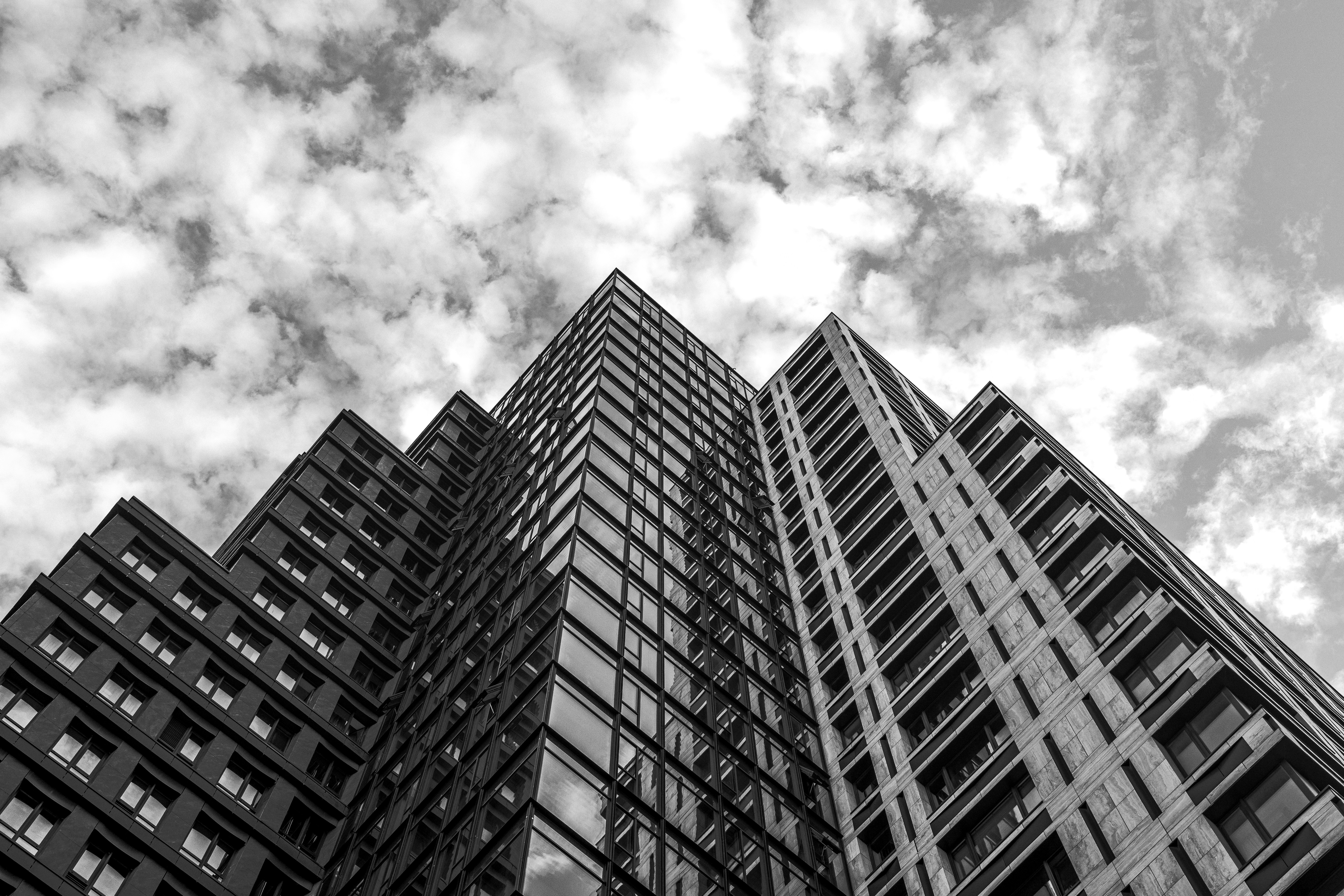 High-rise buildings reaching towards a cloudy sky, showcasing a mix of glass and concrete textures.
