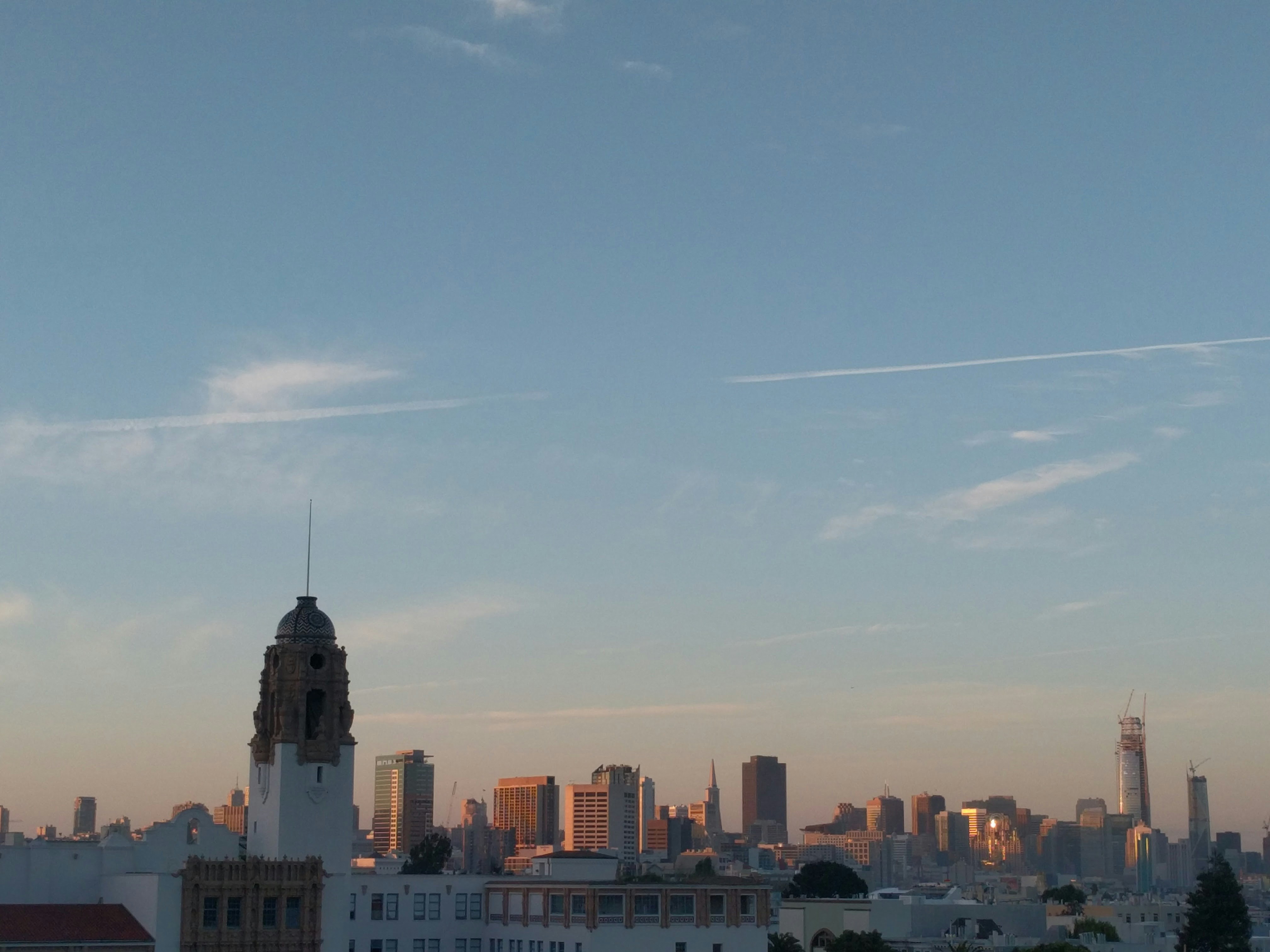 San Francisco skyline under a clear evening sky with scattered clouds.