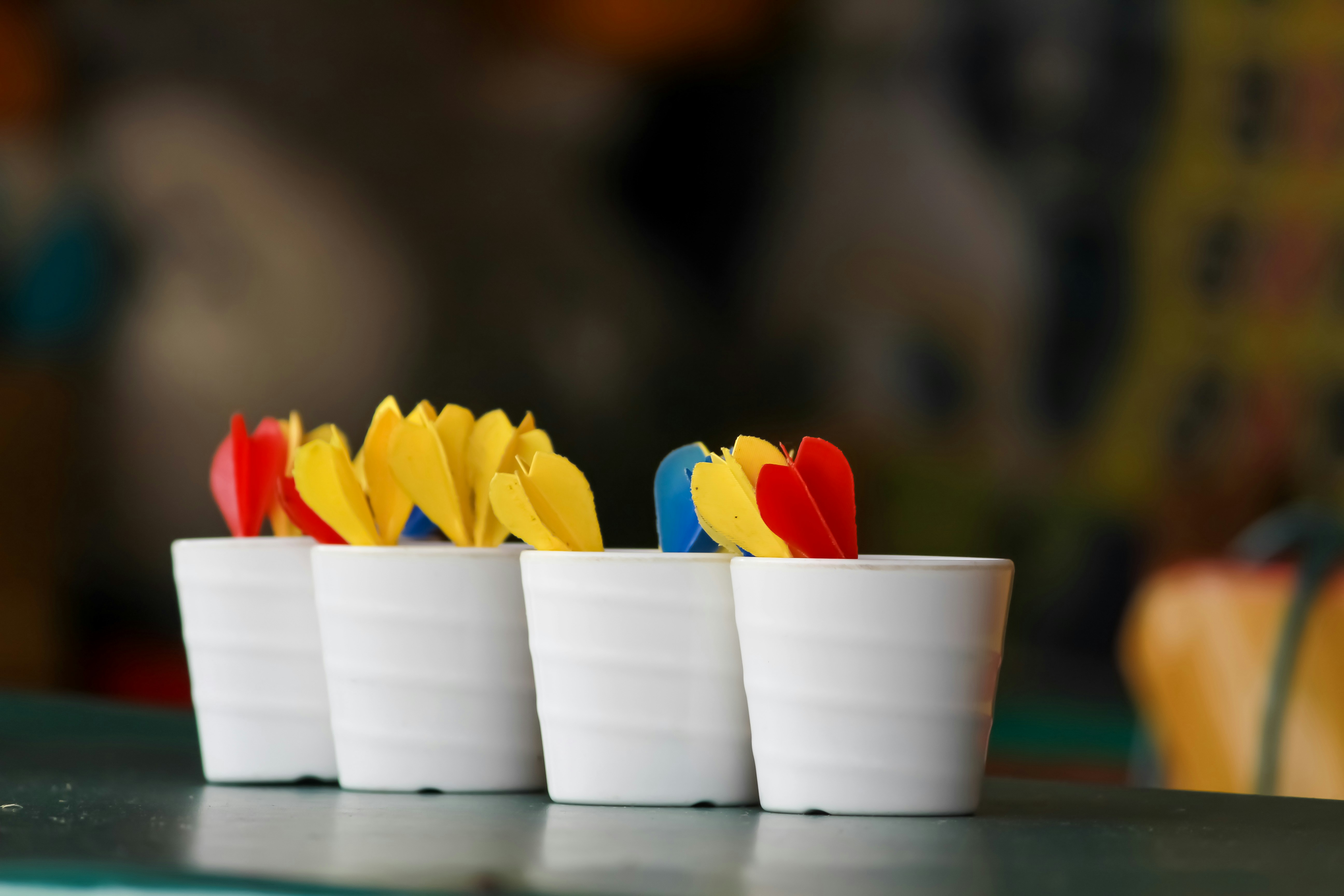 Triad of Colorful Skewers Nestled in White Pots Against a Soft Market Blur