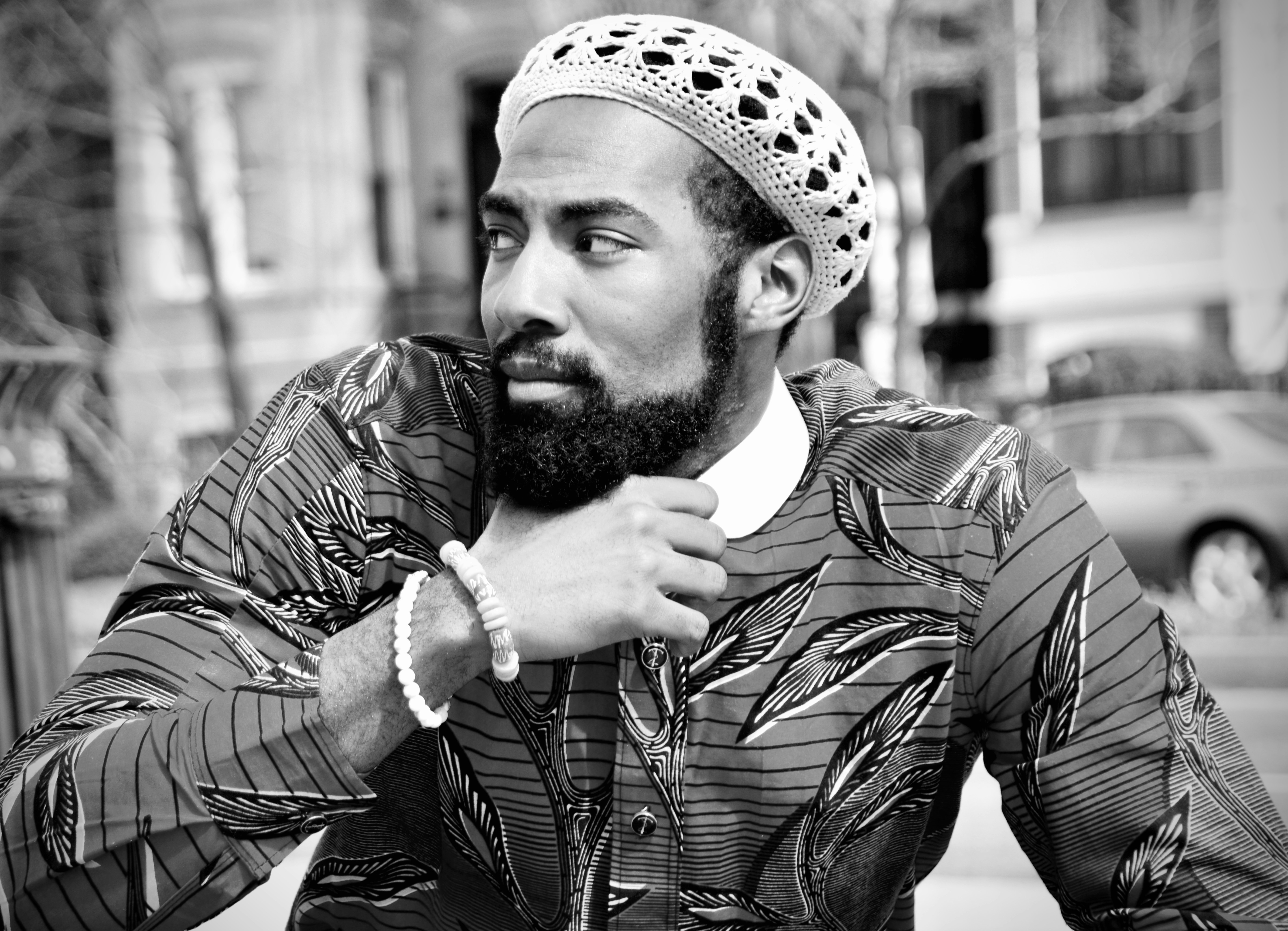 A man in traditional attire with intricate patterns gazes thoughtfully, showcasing a blend of heritage and contemporary style.