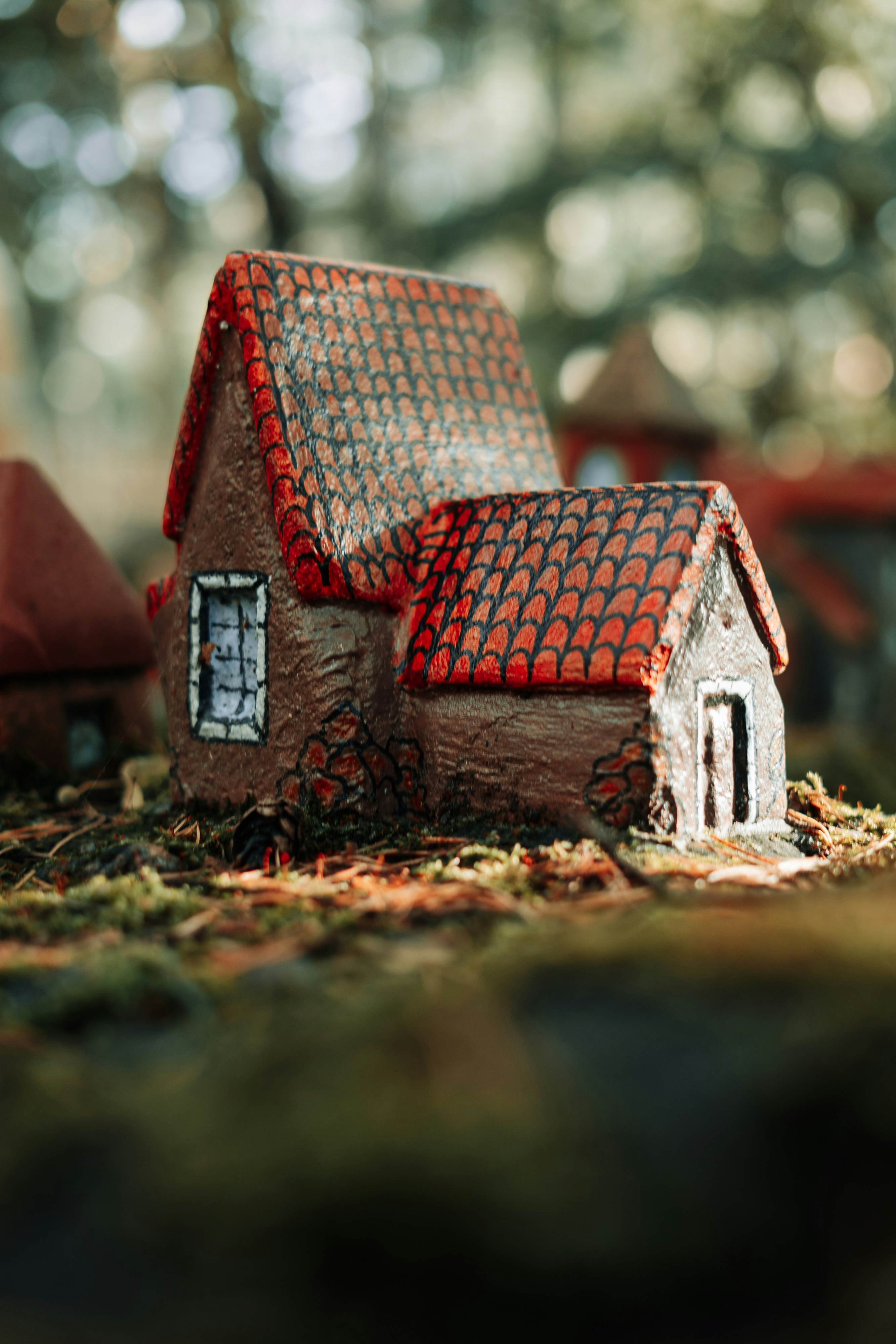 Tiny Village, Large Red Roofs: A Delicate Brick Model in Sunlit Ferns