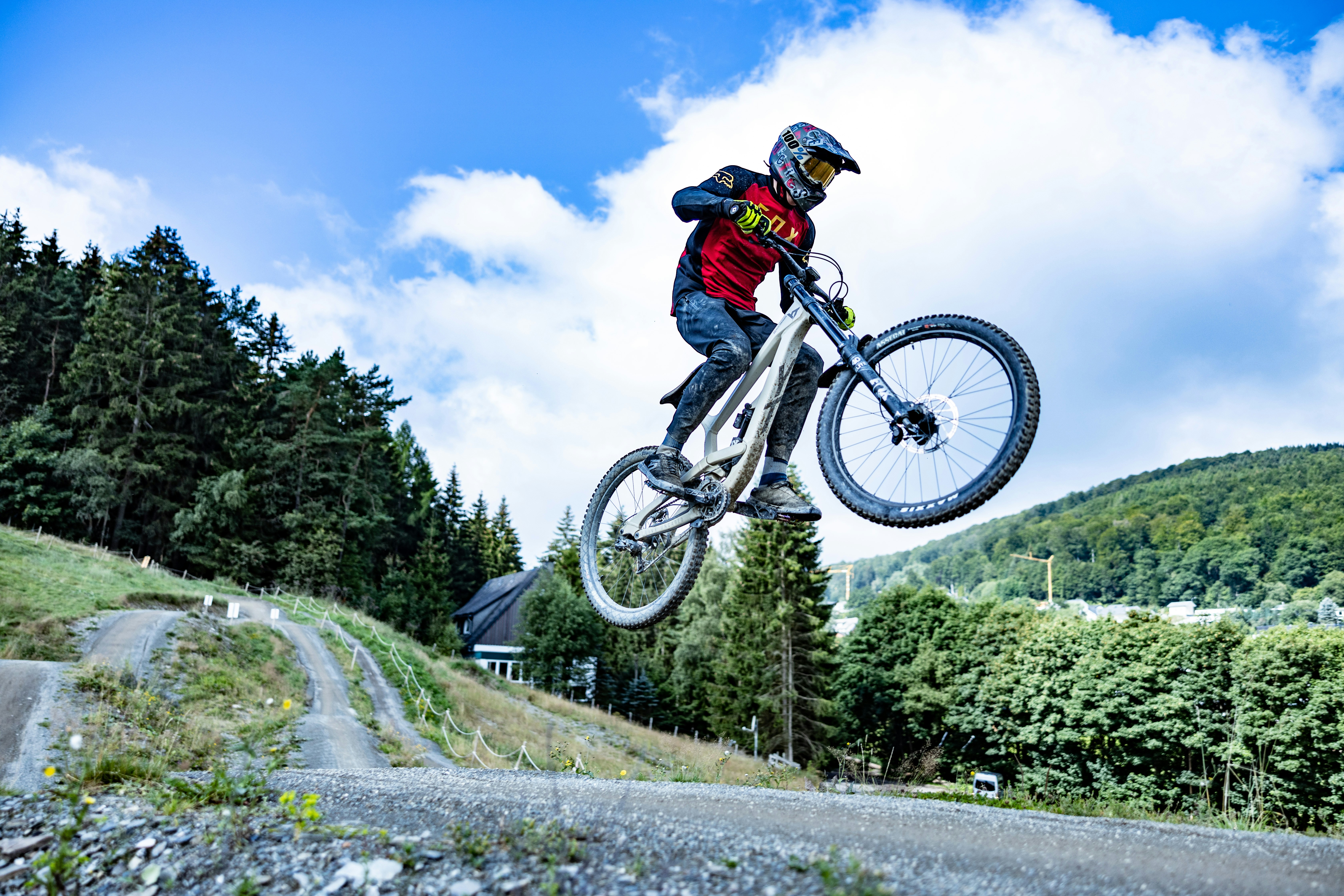 My son jumps with his downhill bike in Willingen, Germany.  | man in black and red jacket riding on motocross dirt bike