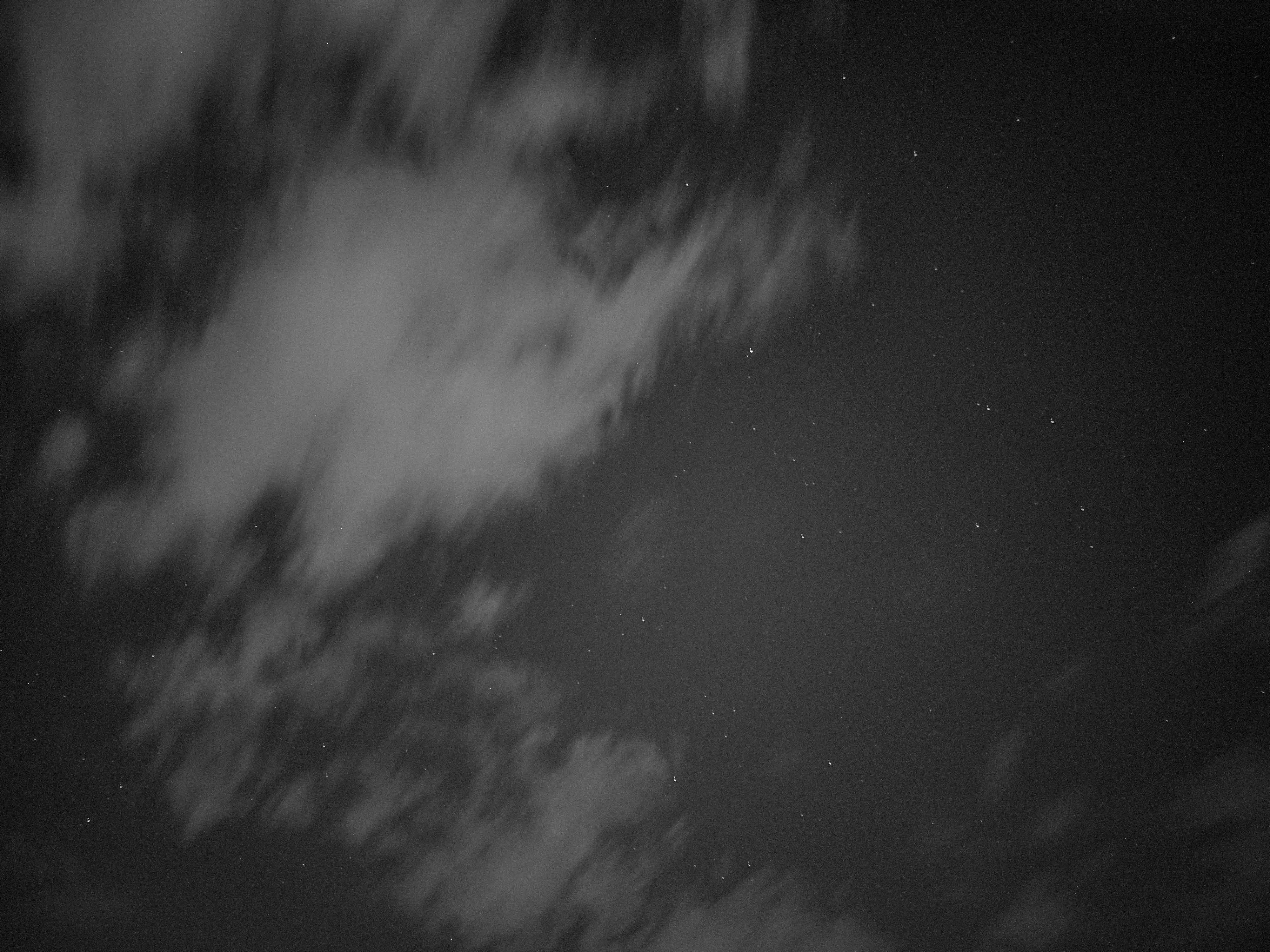 Starry night sky partially obscured by clouds, creating a serene celestial scene.