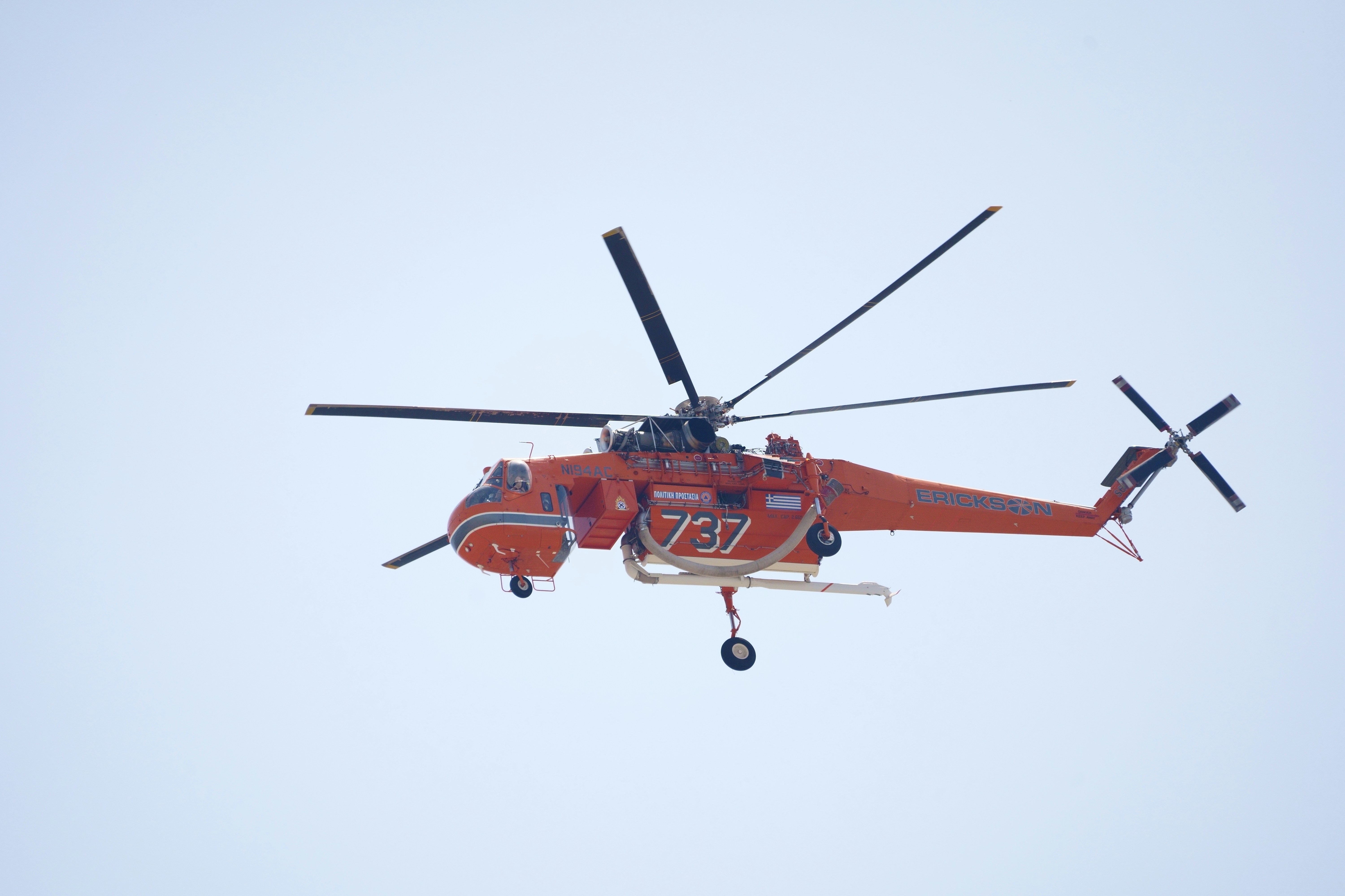 Orange helicopter in flight: rescue-livery silhouette against a pale sky