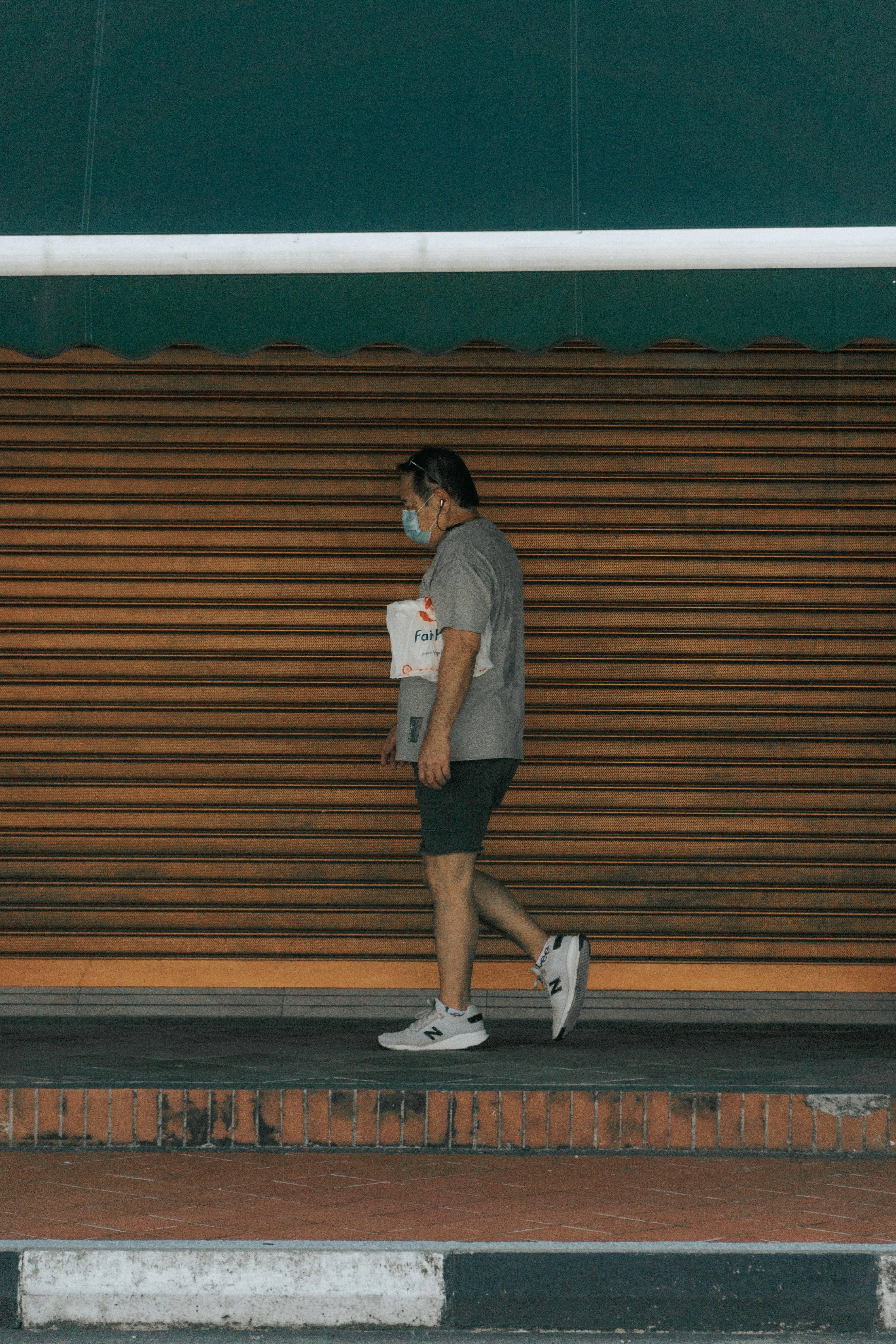 Midstride by a Closed Shopfront Under a Green Awning
