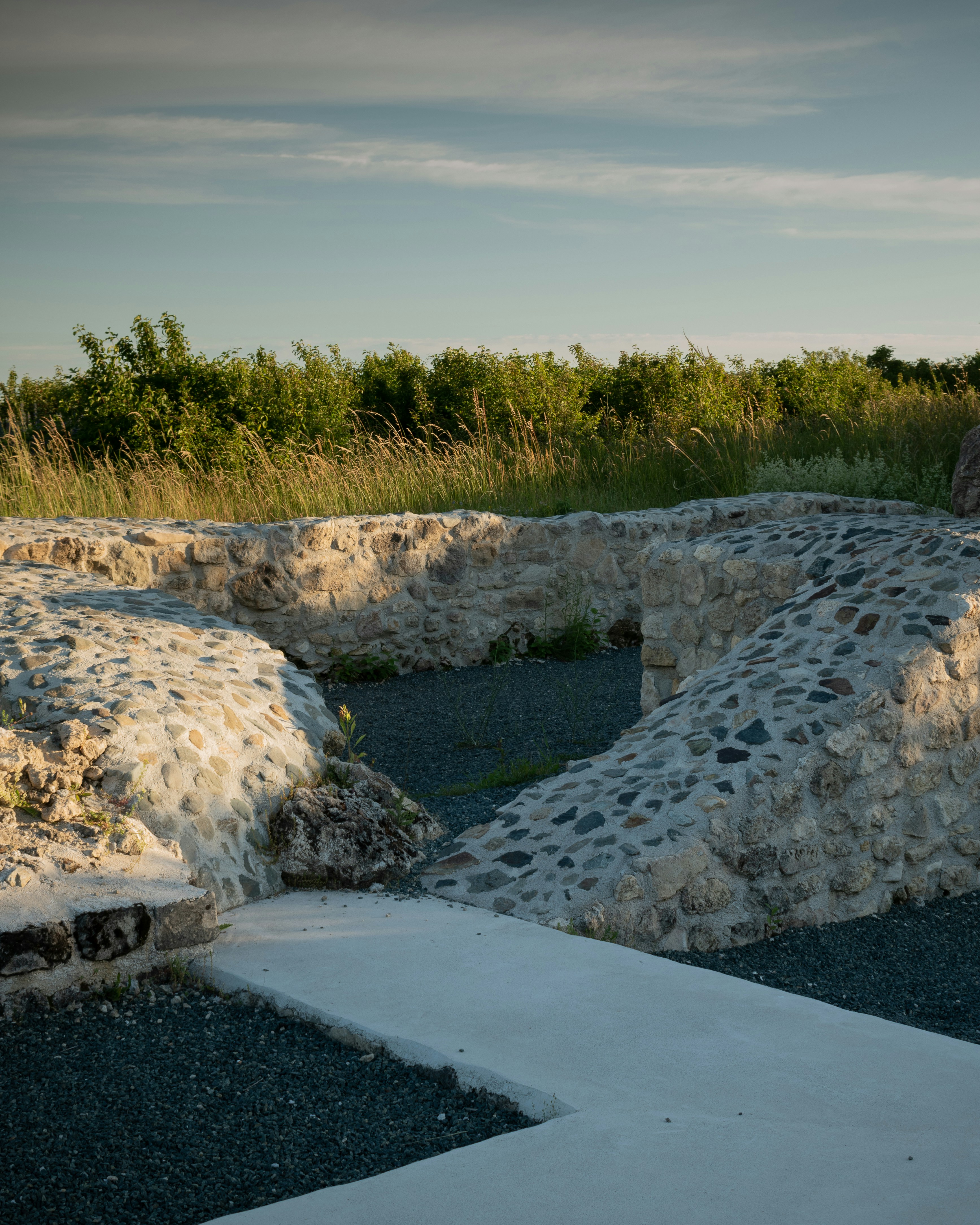 Rudina | gray concrete pathway between green grass field under white clouds during daytime