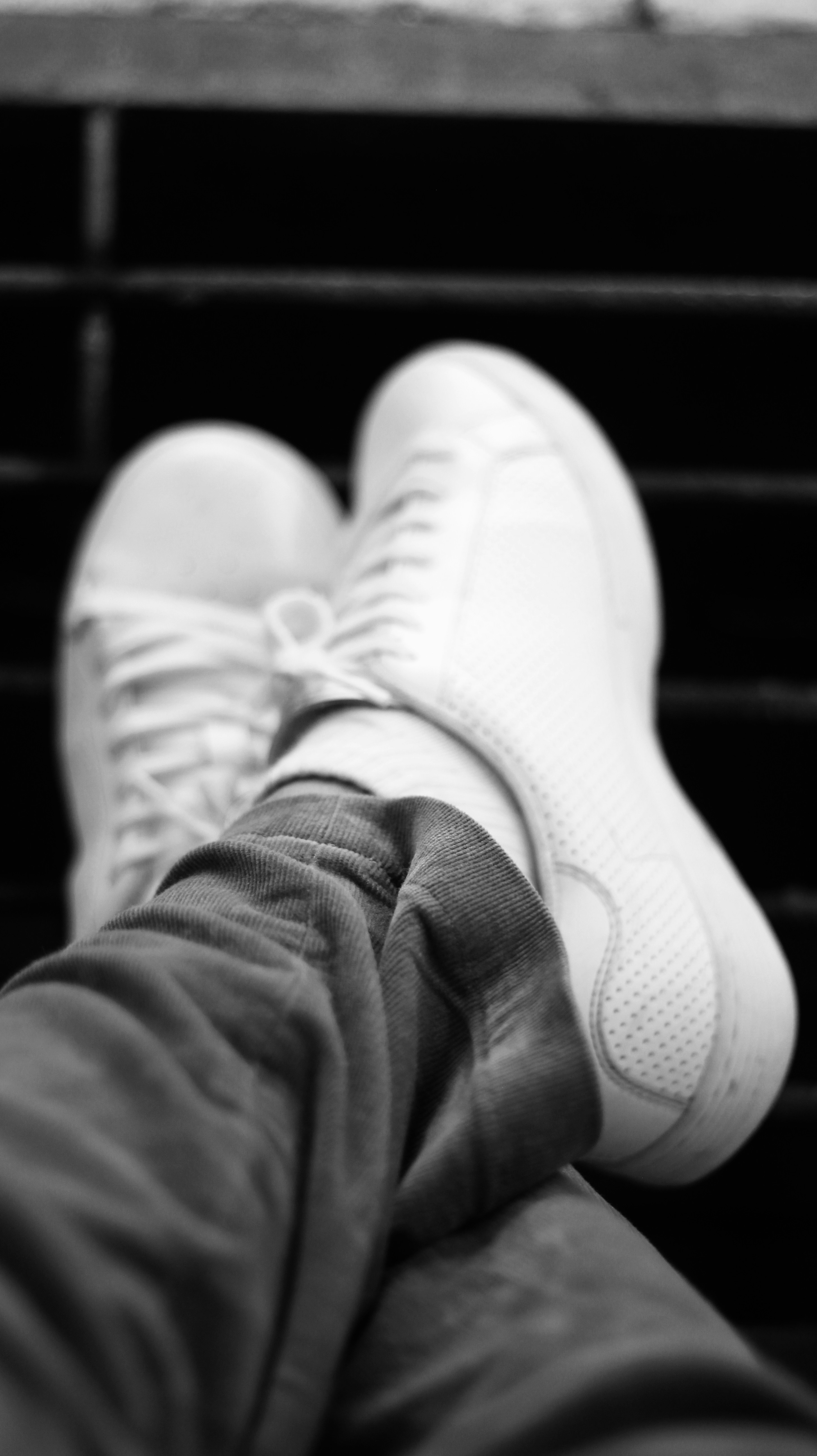 Close-up of white sneakers resting on a textured surface, showcasing a modern, minimalist aesthetic.