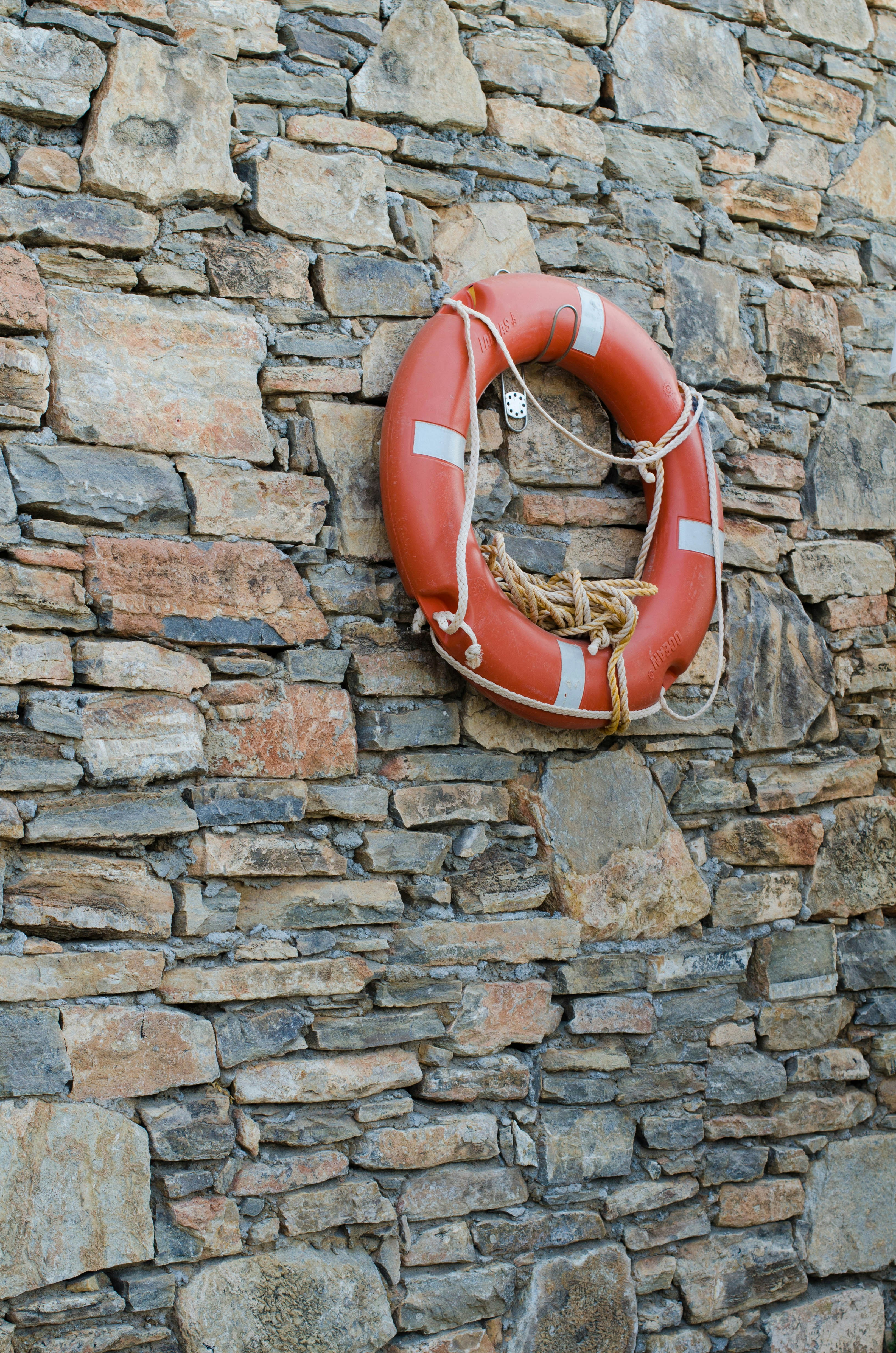 Red Lifebuoy on a Weathered Stone Wall