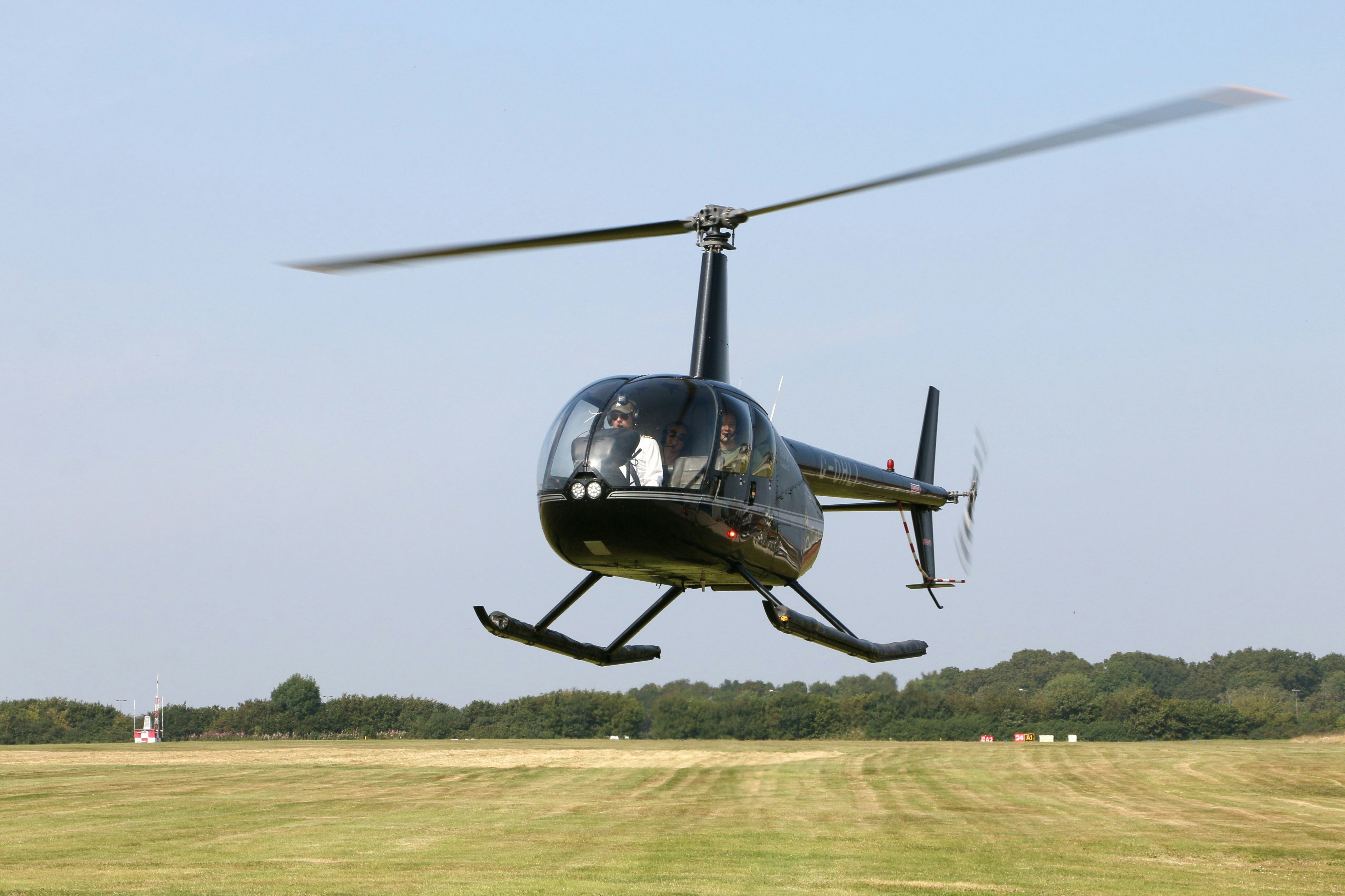 Black helicopter flying over green grass field during daytime photo ...