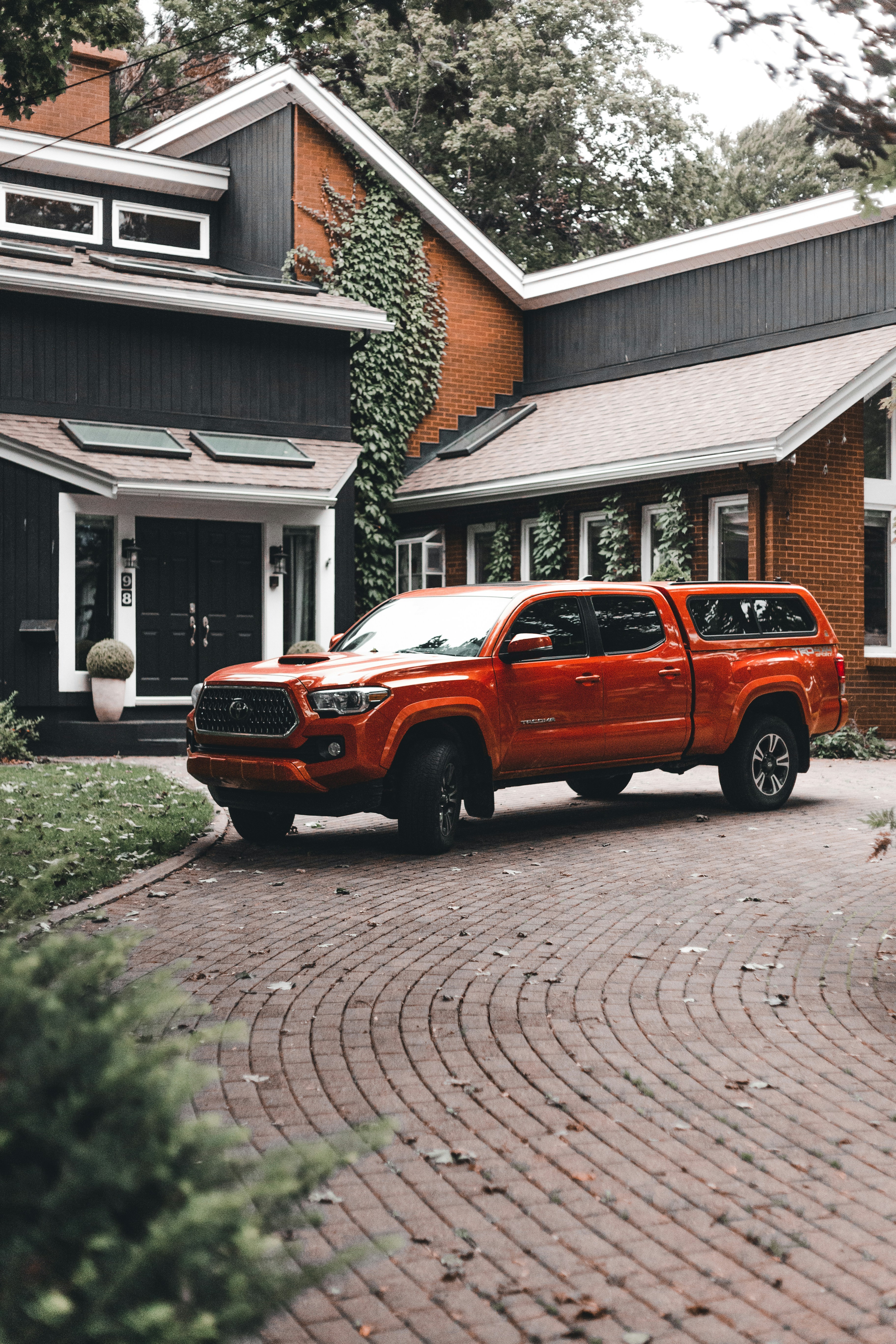 Crimson-Orange Pickup Graces a Curved Brick Driveway Before a Contemporary Home
