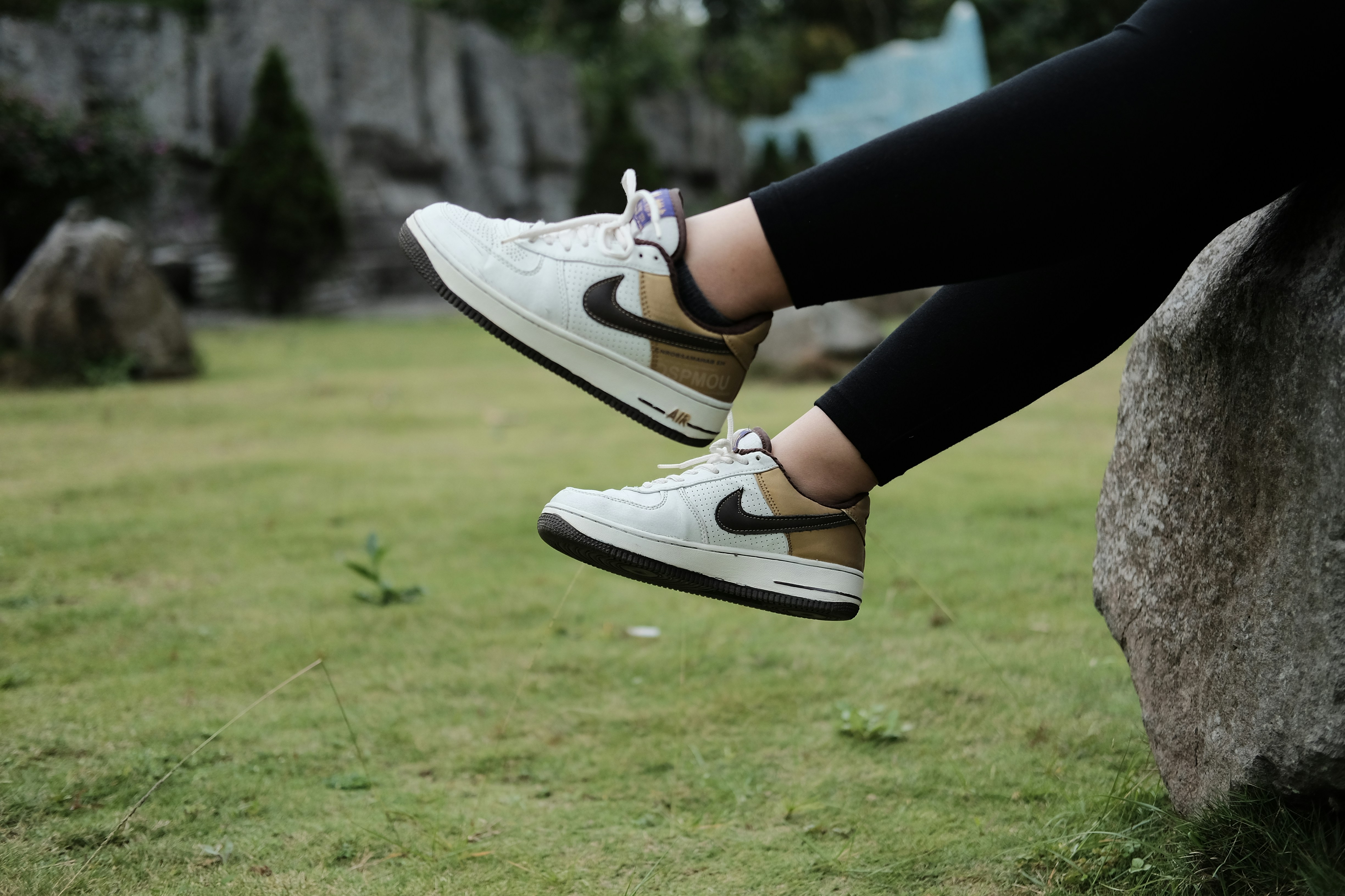 person in black pants and white nike sneakers