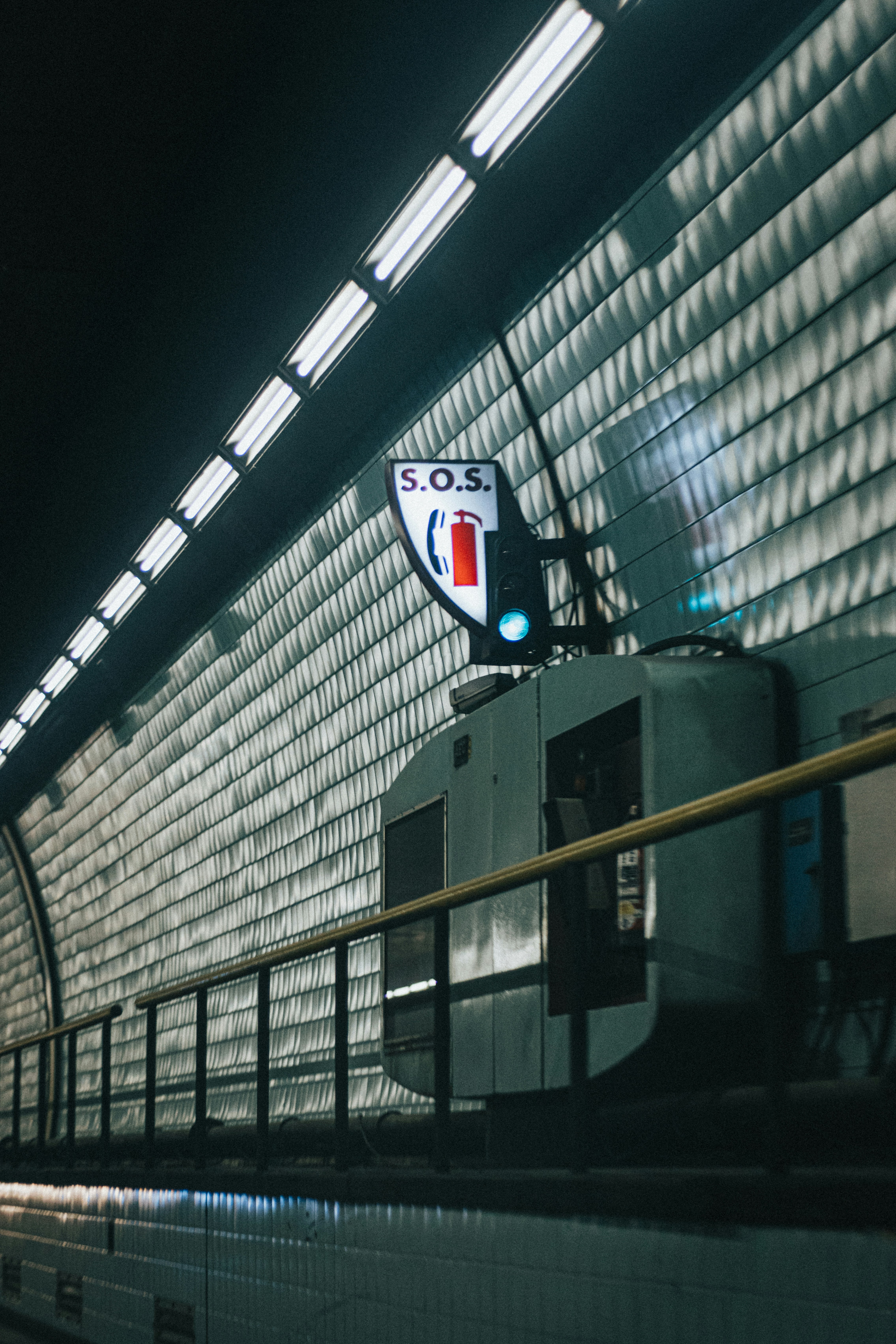 Illuminated emergency signal in a subway tunnel, reflecting off the tiled walls. A train carriage is partially visible, emphasizing the urban environment.