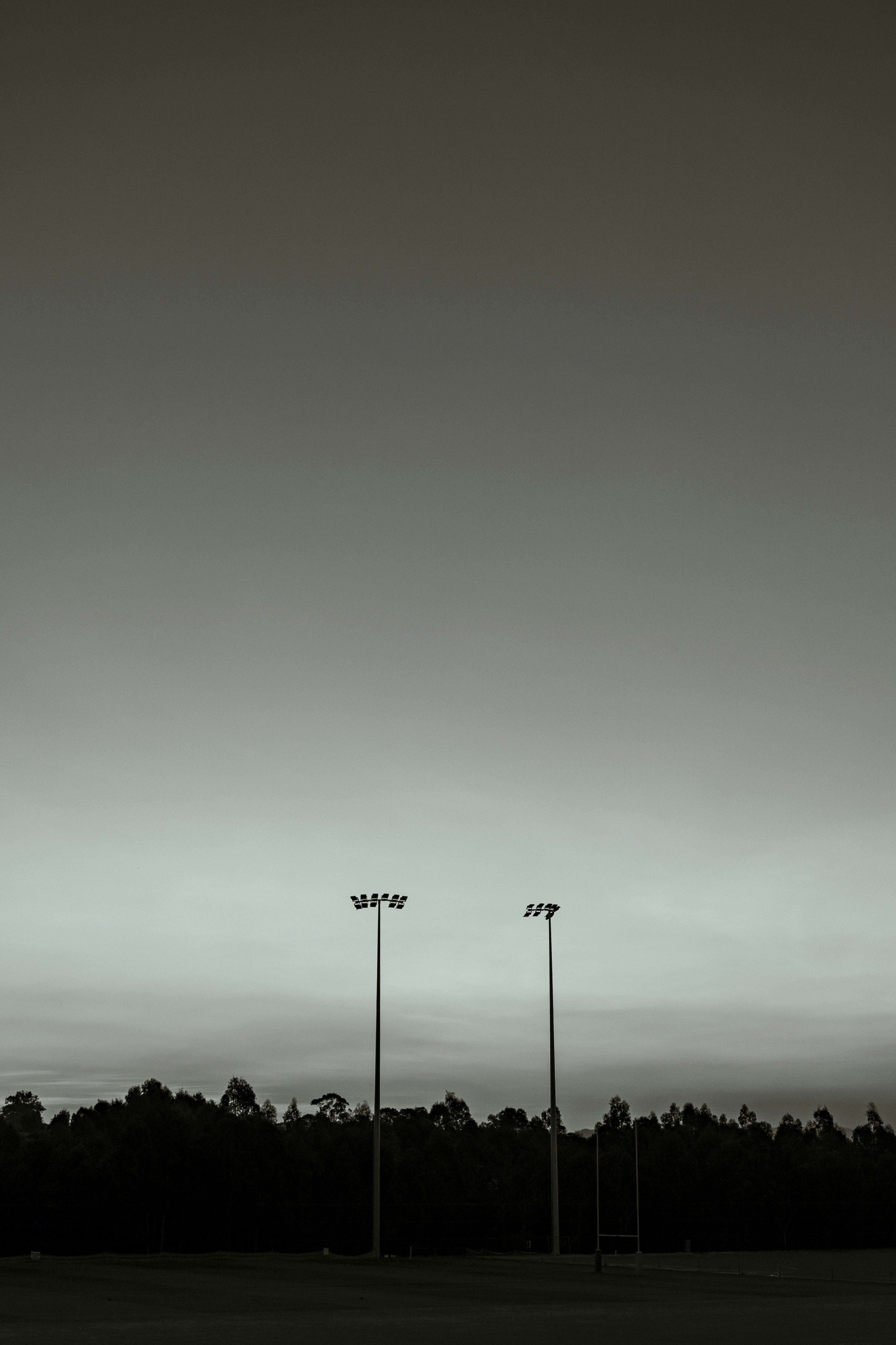 Dusk's Silent Sentinels: Twin Floodlights Over a Quiet Field