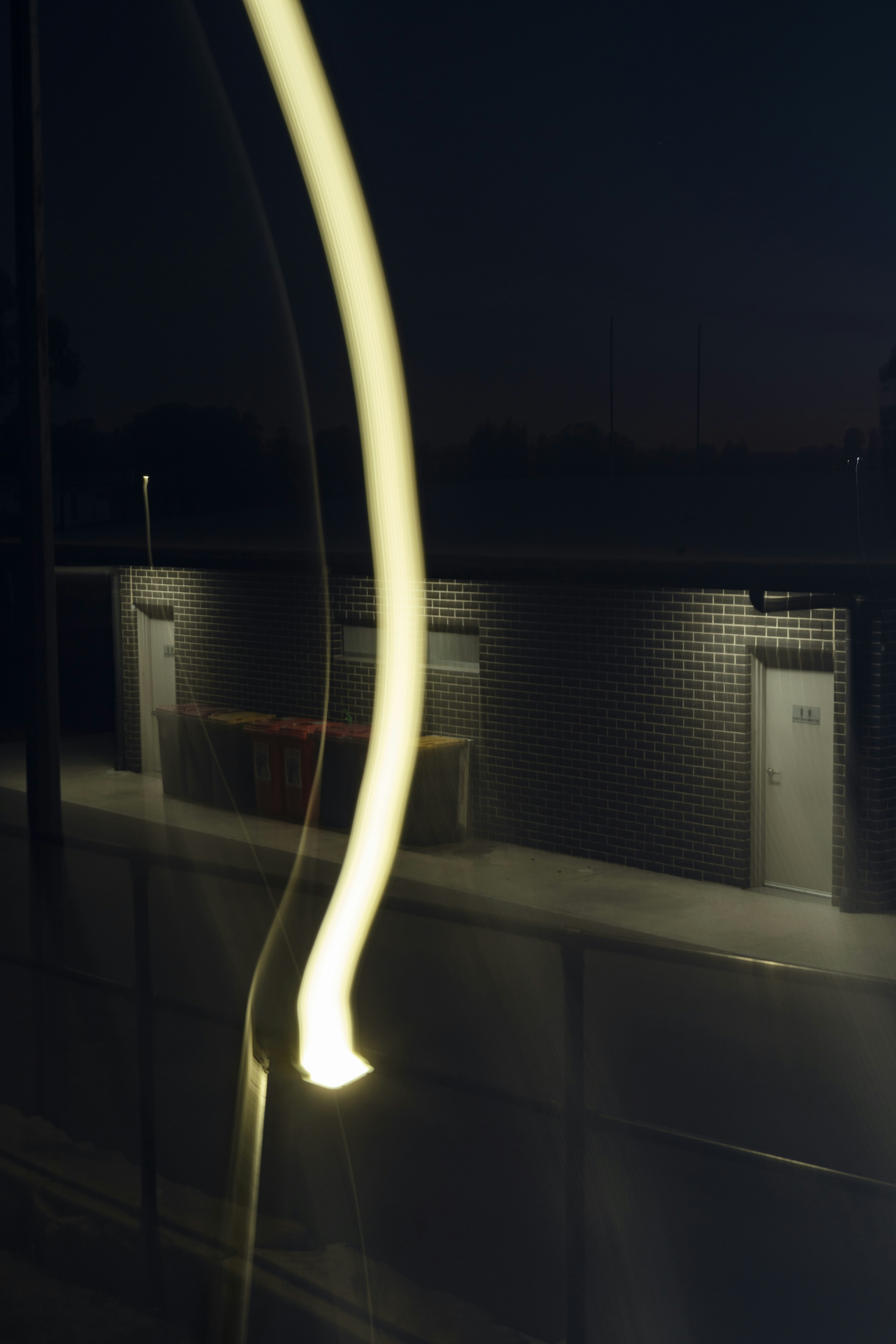 Neon Ribbon in Slow Motion: Long-Exposure Along a Brick Utility Facade