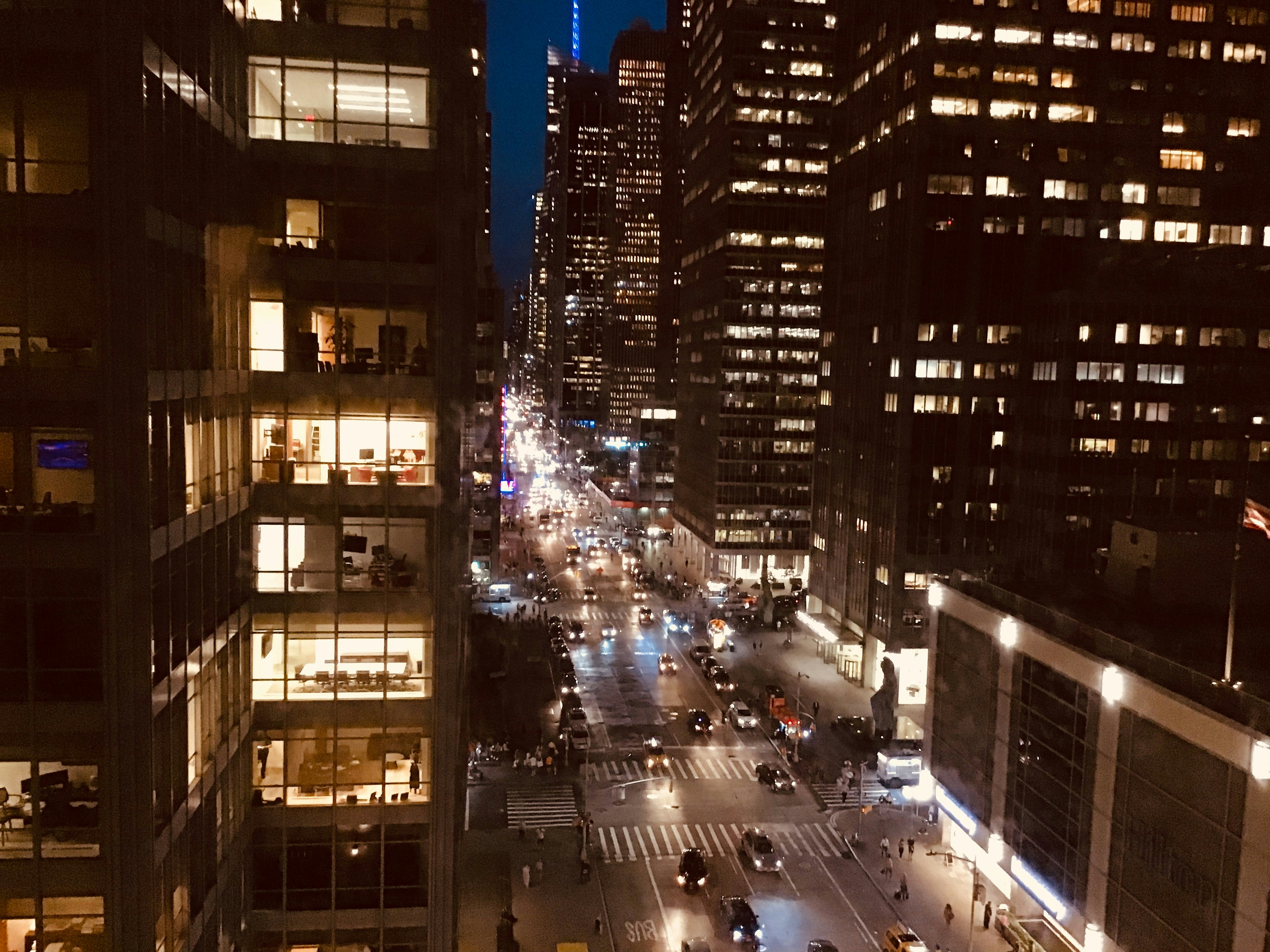 Cars on road in between high rise buildings during night time photo ...