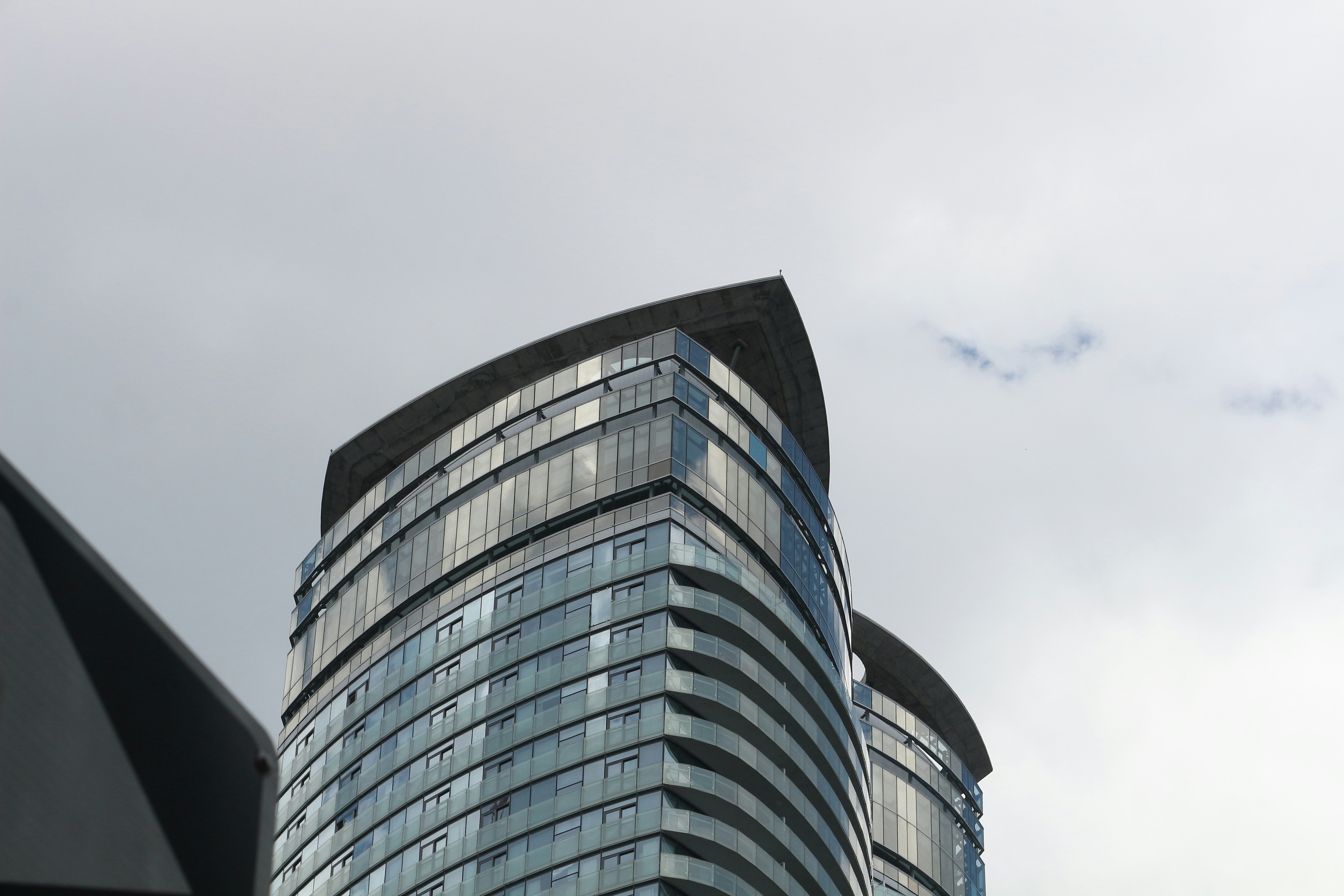Curved Glass Tower Reaching Toward the Cloudy Sky