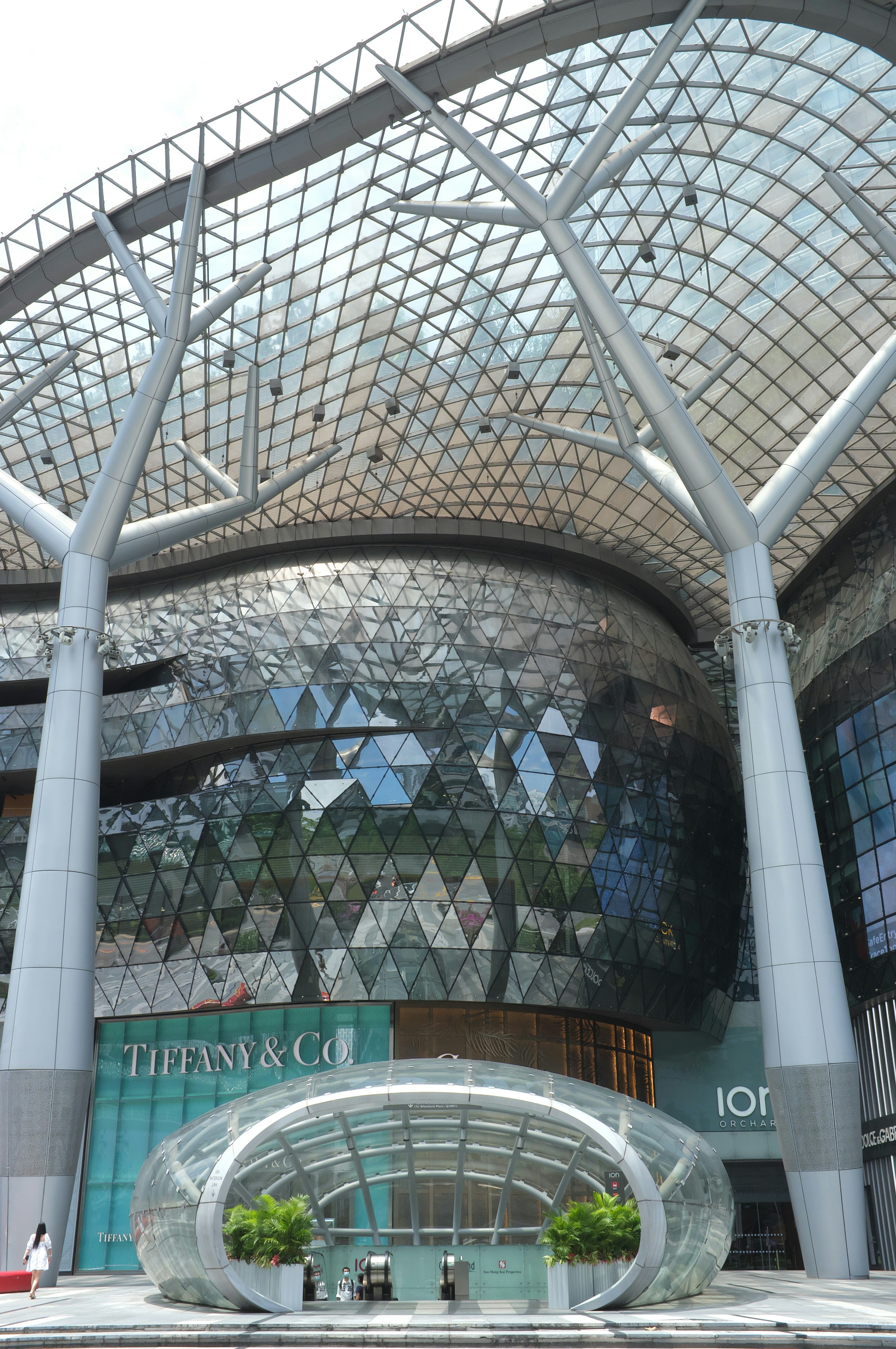 Architectural marvel featuring a glass façade with geometric patterns, showcasing the entrance of Tiffany & Co. at a luxury shopping center.