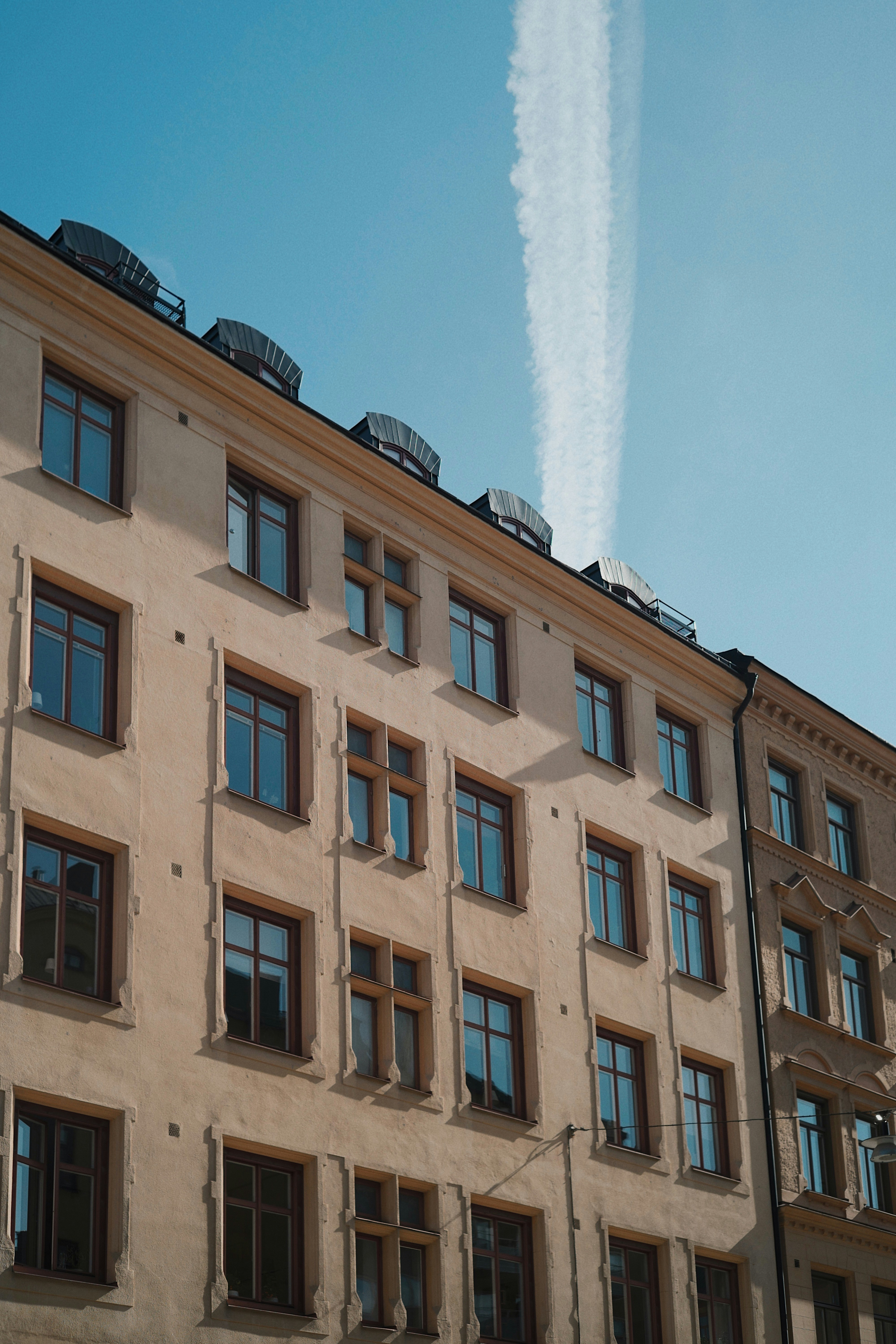 Jet Trail Over a Sunlit City Block