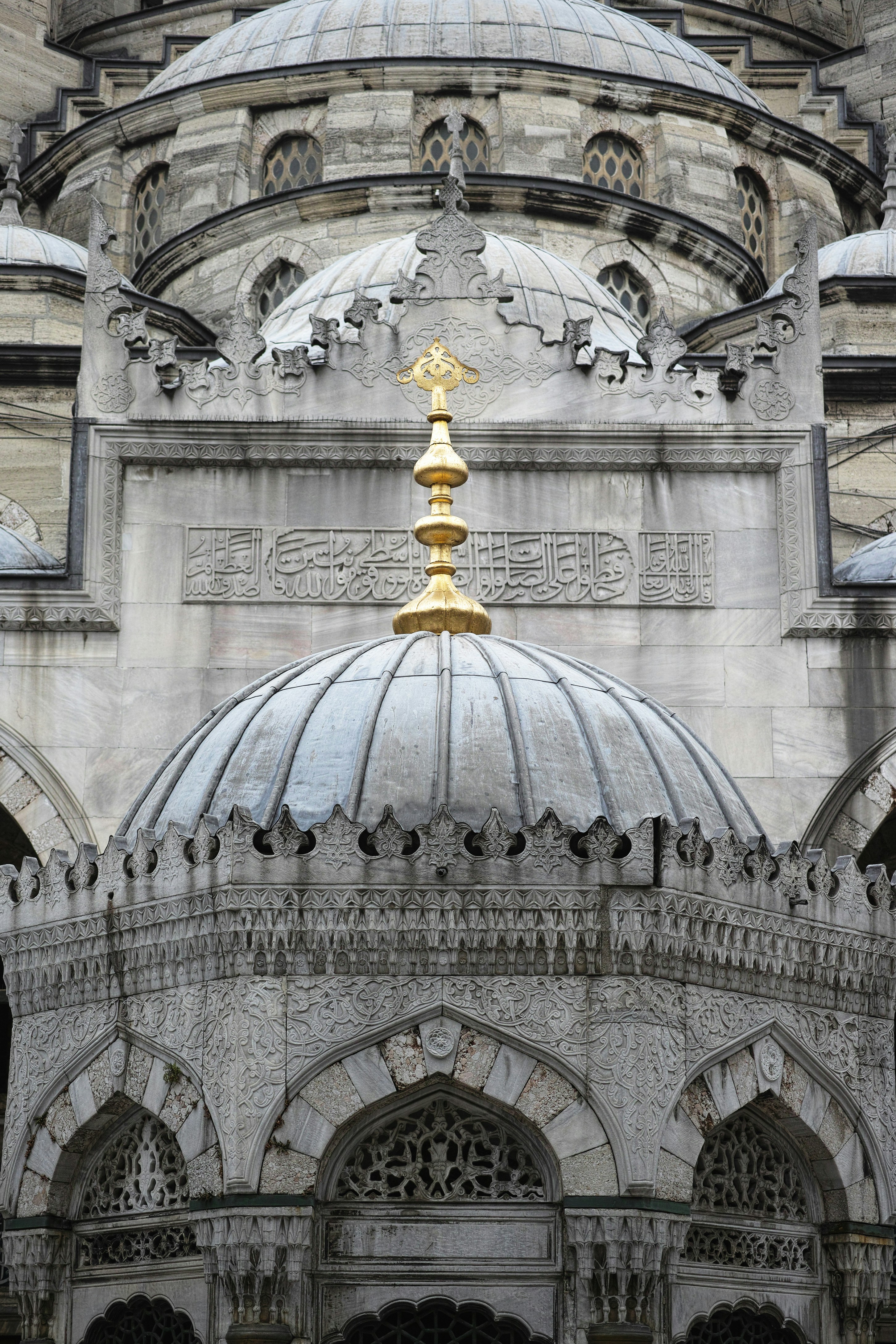Golden Finial Above Marble Domes: A Mosque's Ornate Frieze and Archway