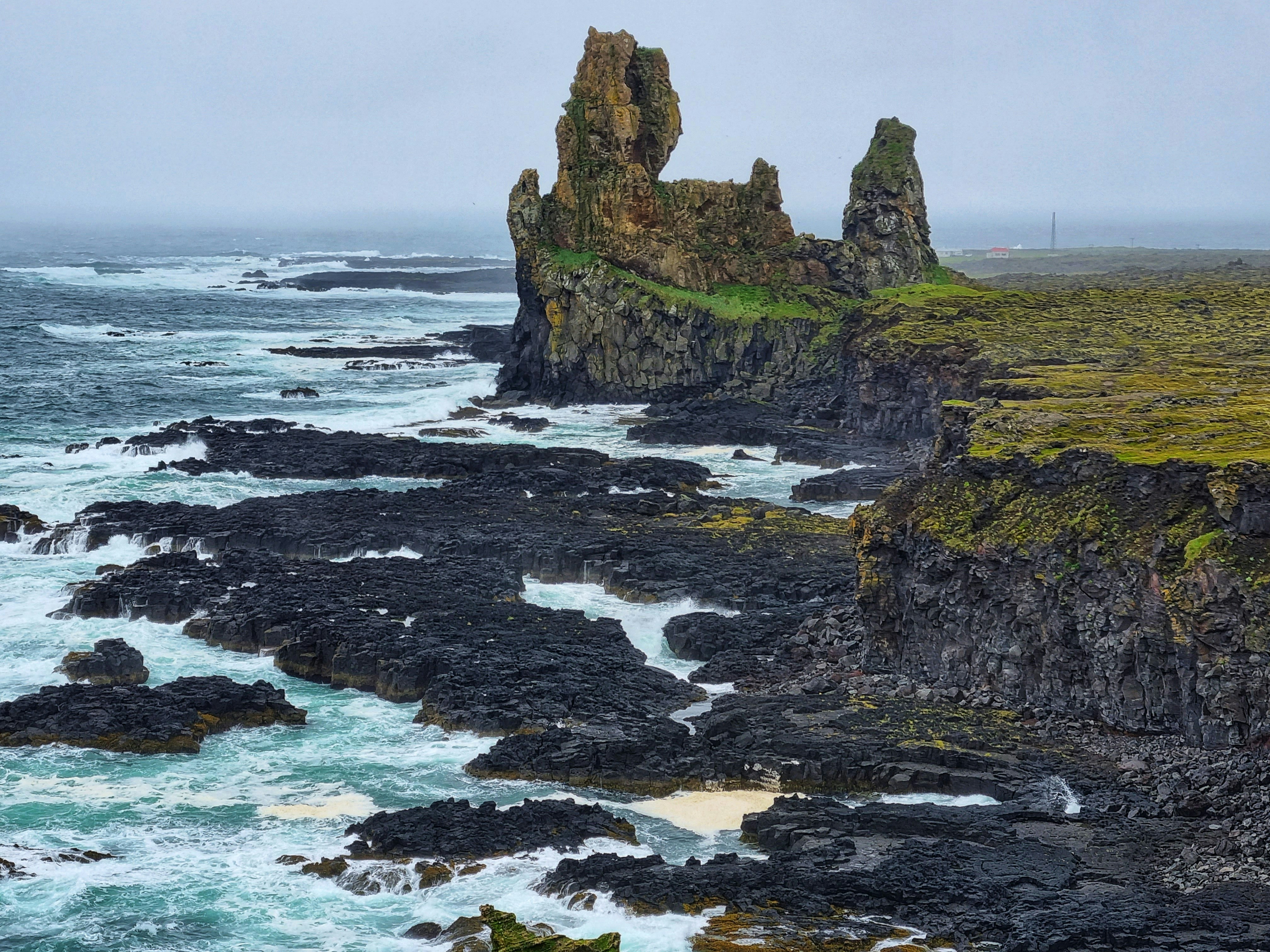 Rock formations at Snaefellsnes peninsula in west Iceland | brown and green rock formation on sea during daytime