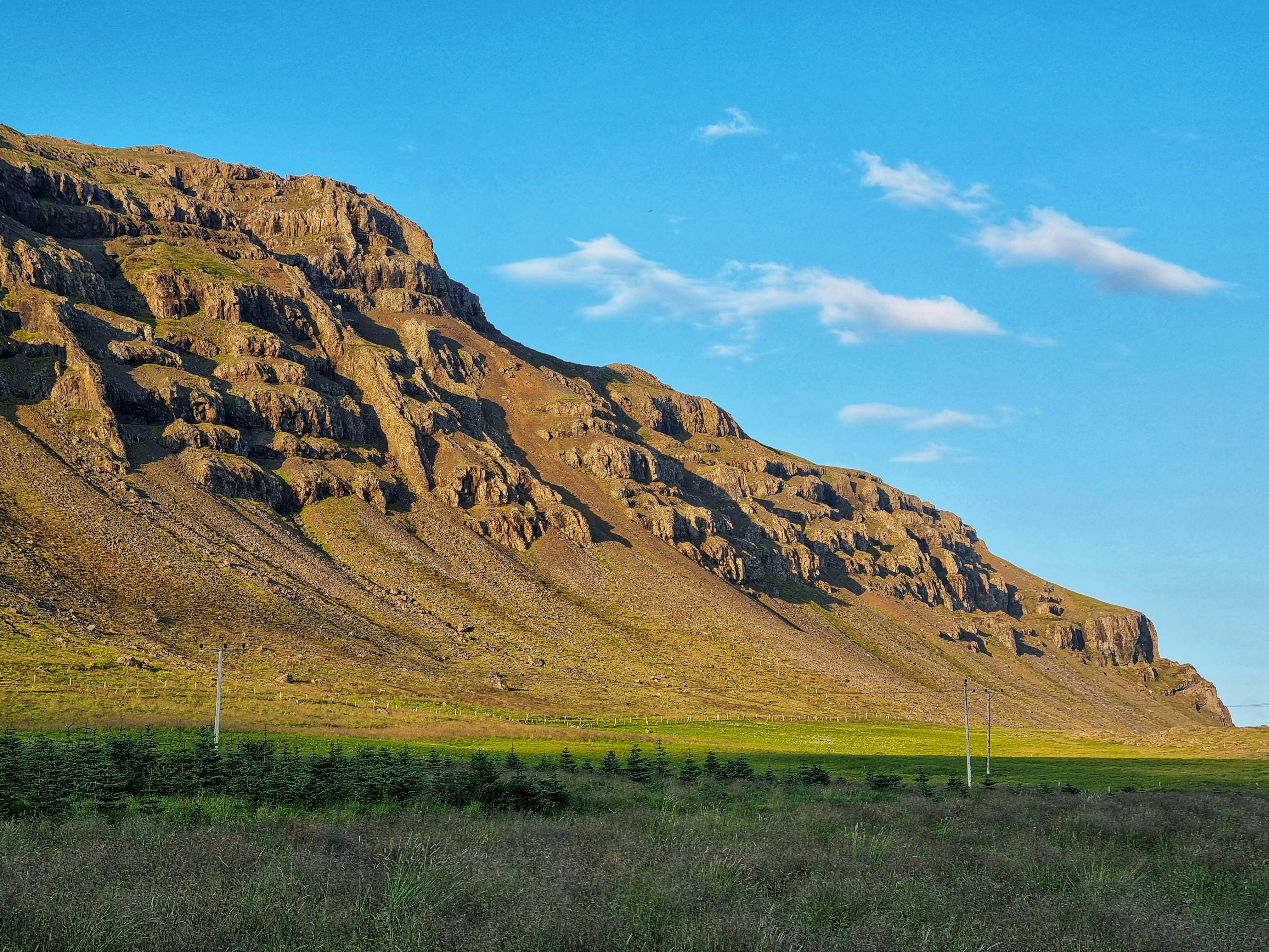 Rocky cliffs bathed in warm sunset light under a clear blue sky.