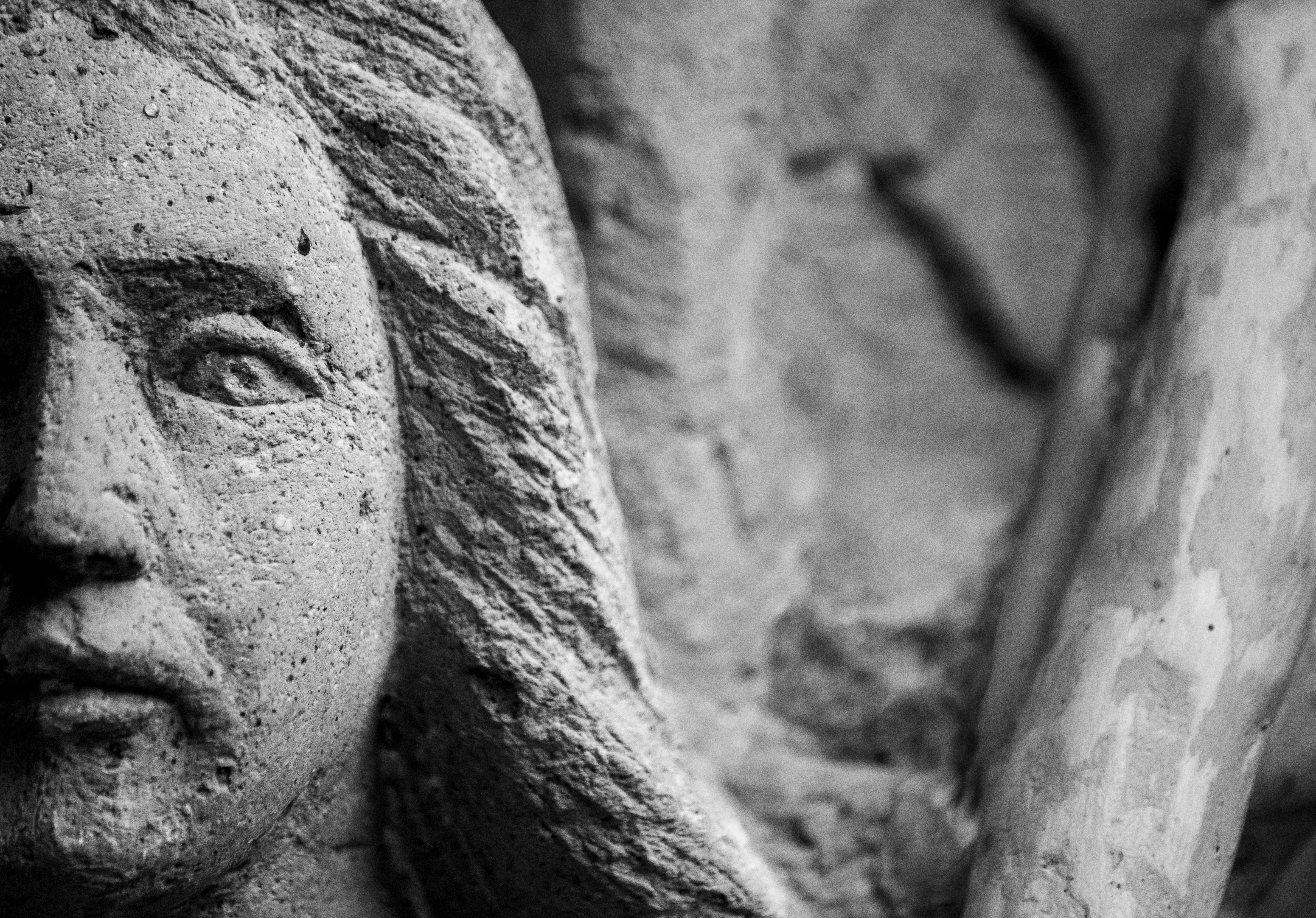 Close-up of a stone sculpture's face with intricate details and textures.