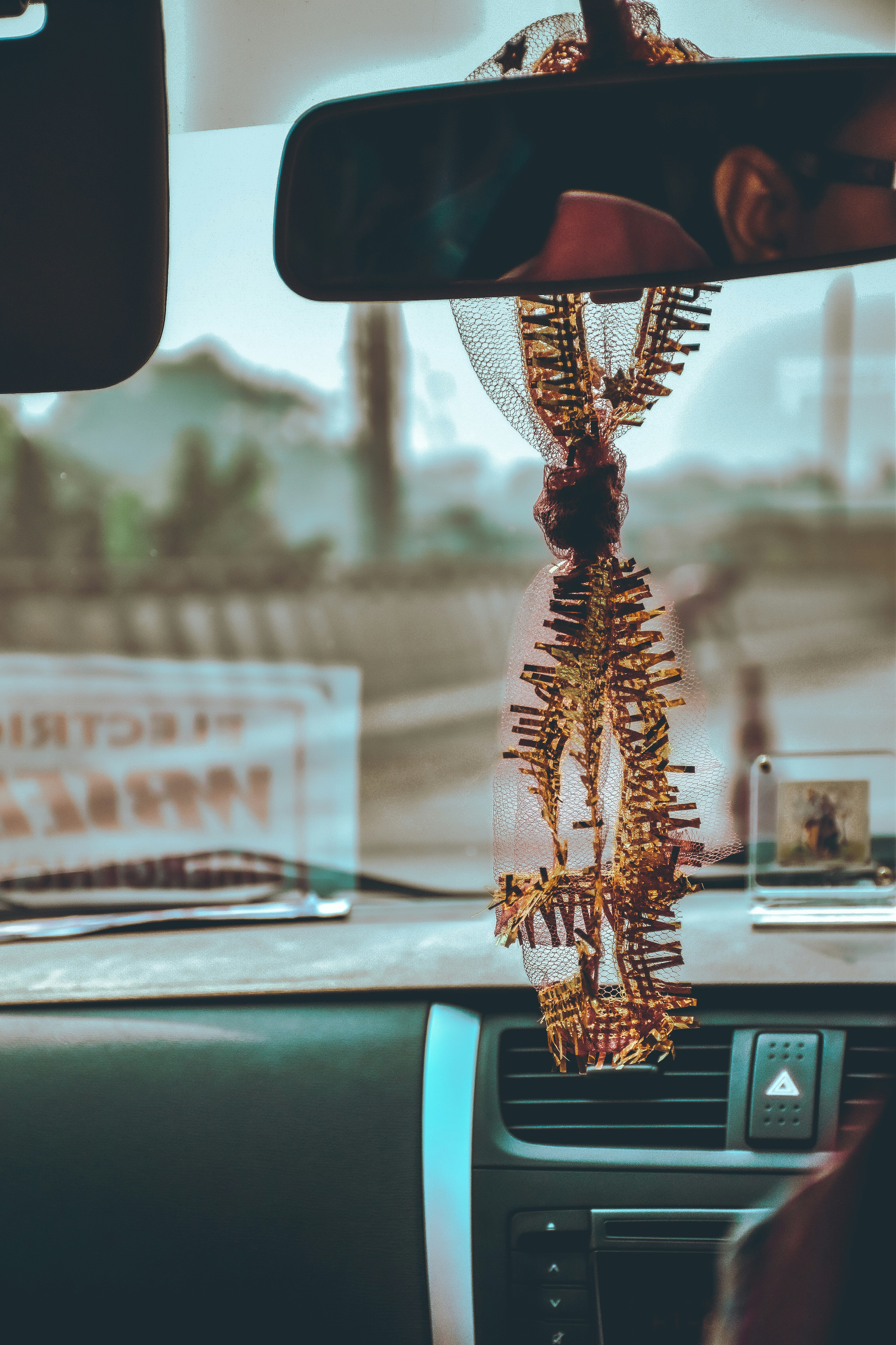 Hanging Talisman: Beaded Ornament in a Car’s Windshield Backdrop