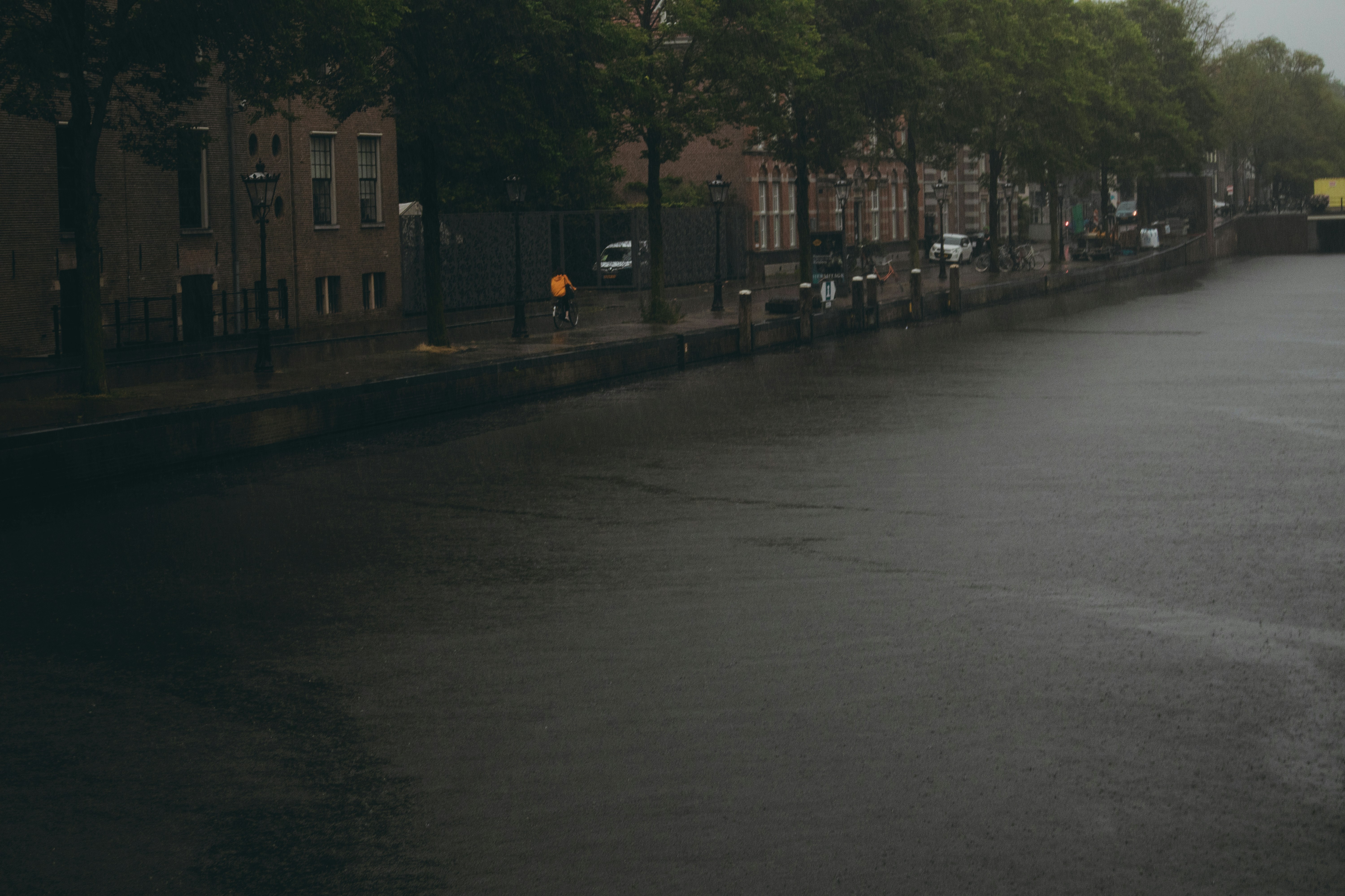 Yellow-Clad Figure Along a Rain-Slick Canal at Dusk
