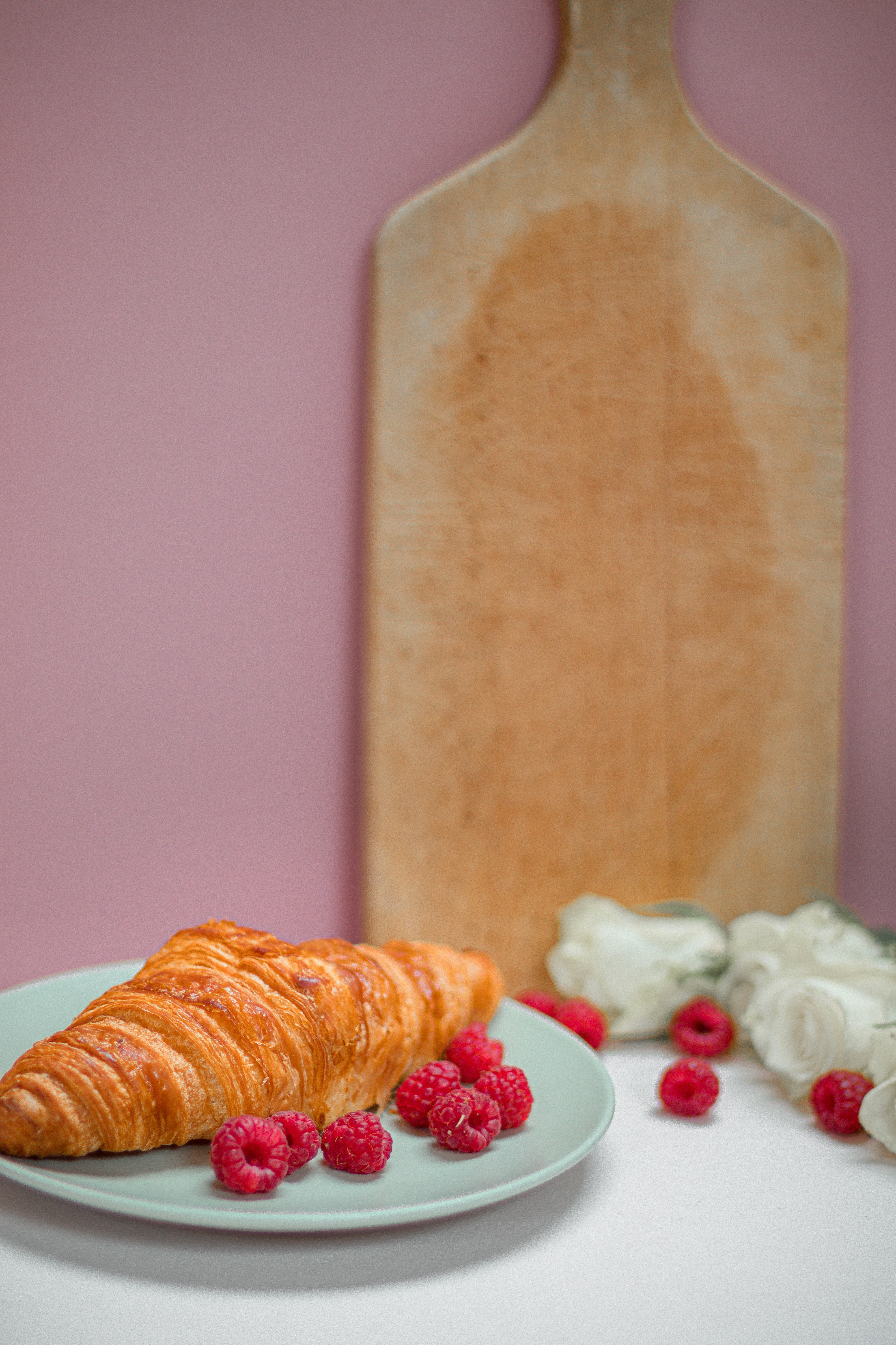 Pastel Still Life: Golden Croissant on a Pale Plate with Raspberry Accents