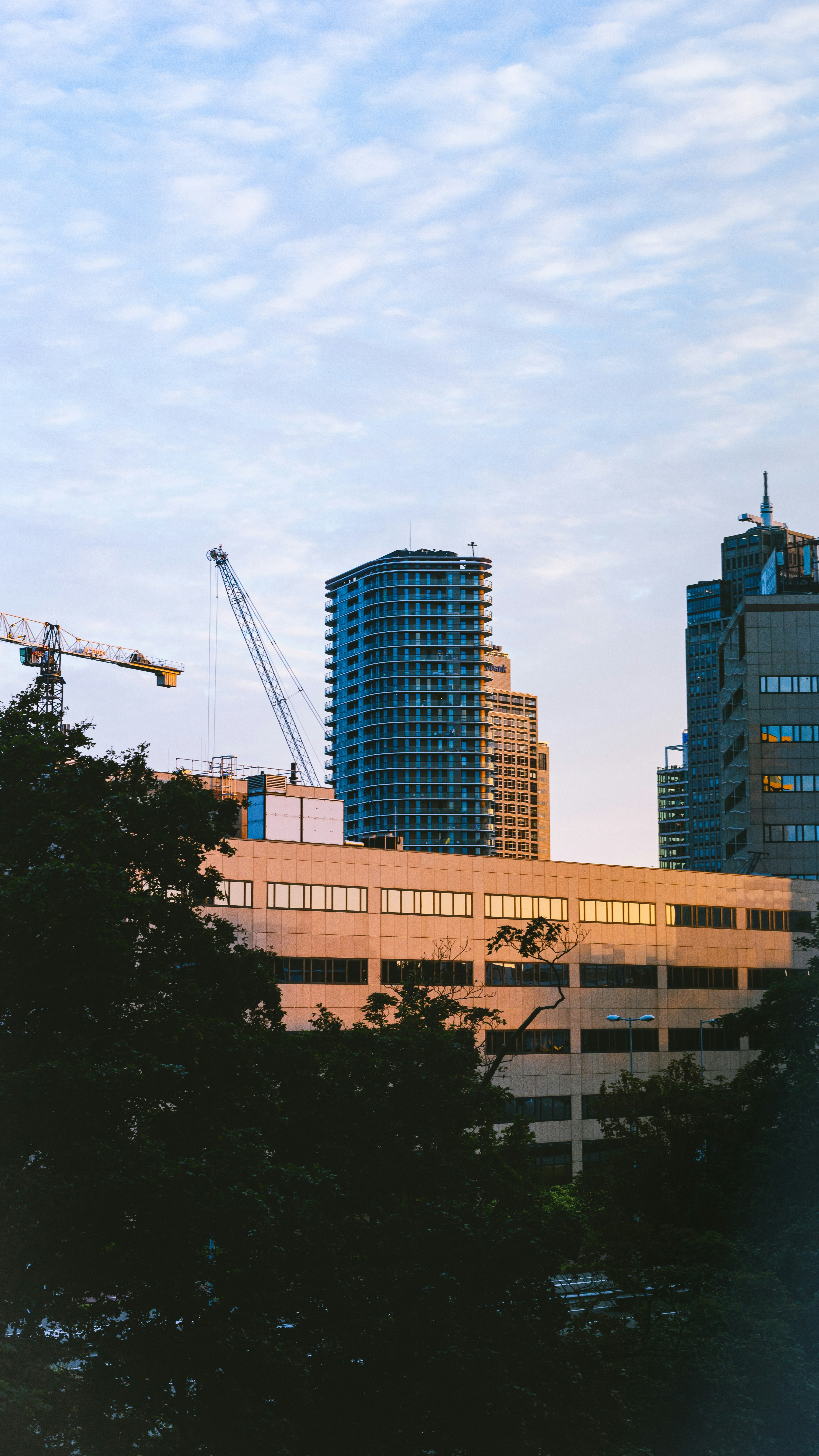 Azure Glass Tower at Golden Hour: A Crane-Wired Cityscape