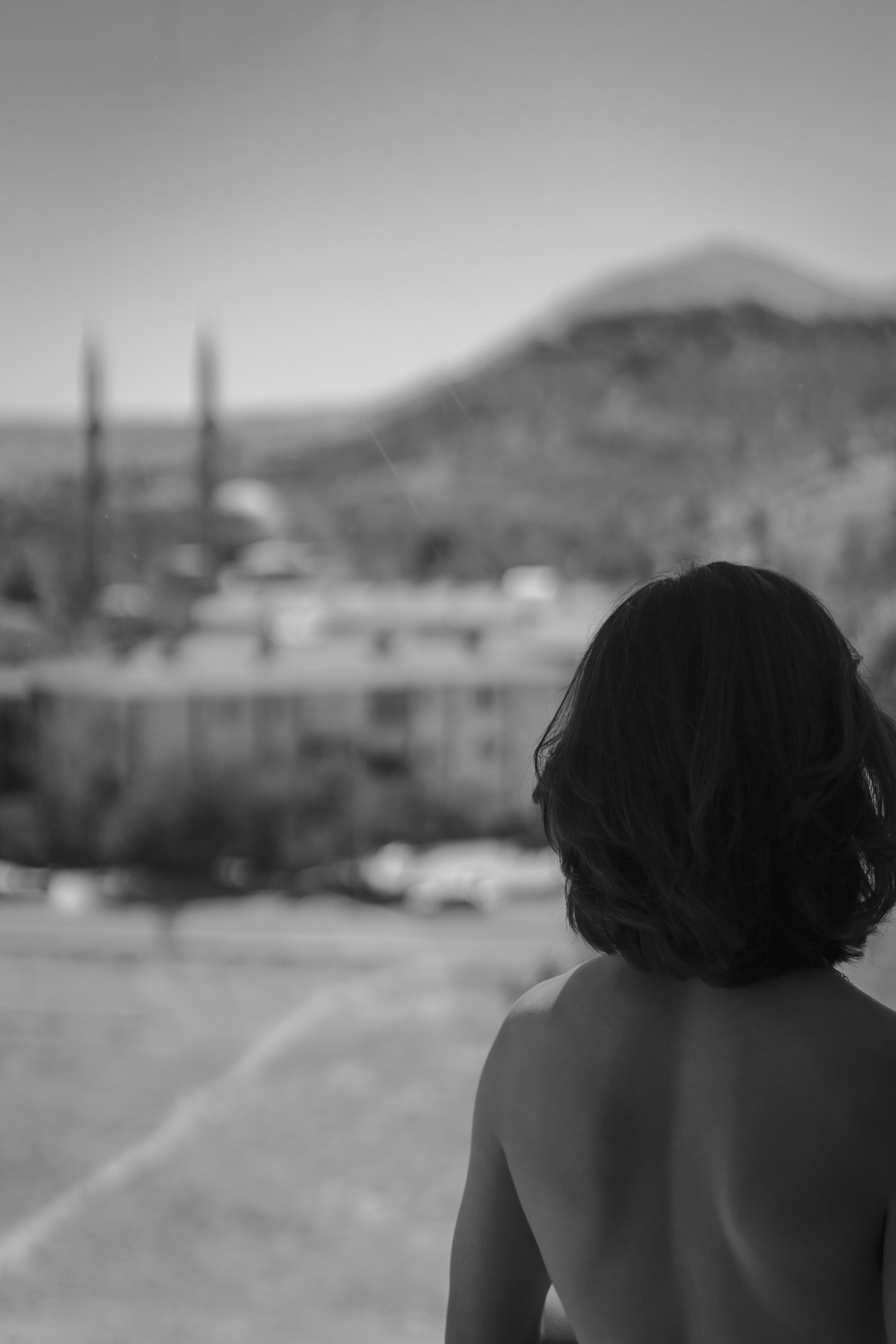 Backlit Portrait by the Shore: Hair, Shoulder, and Distant Industry