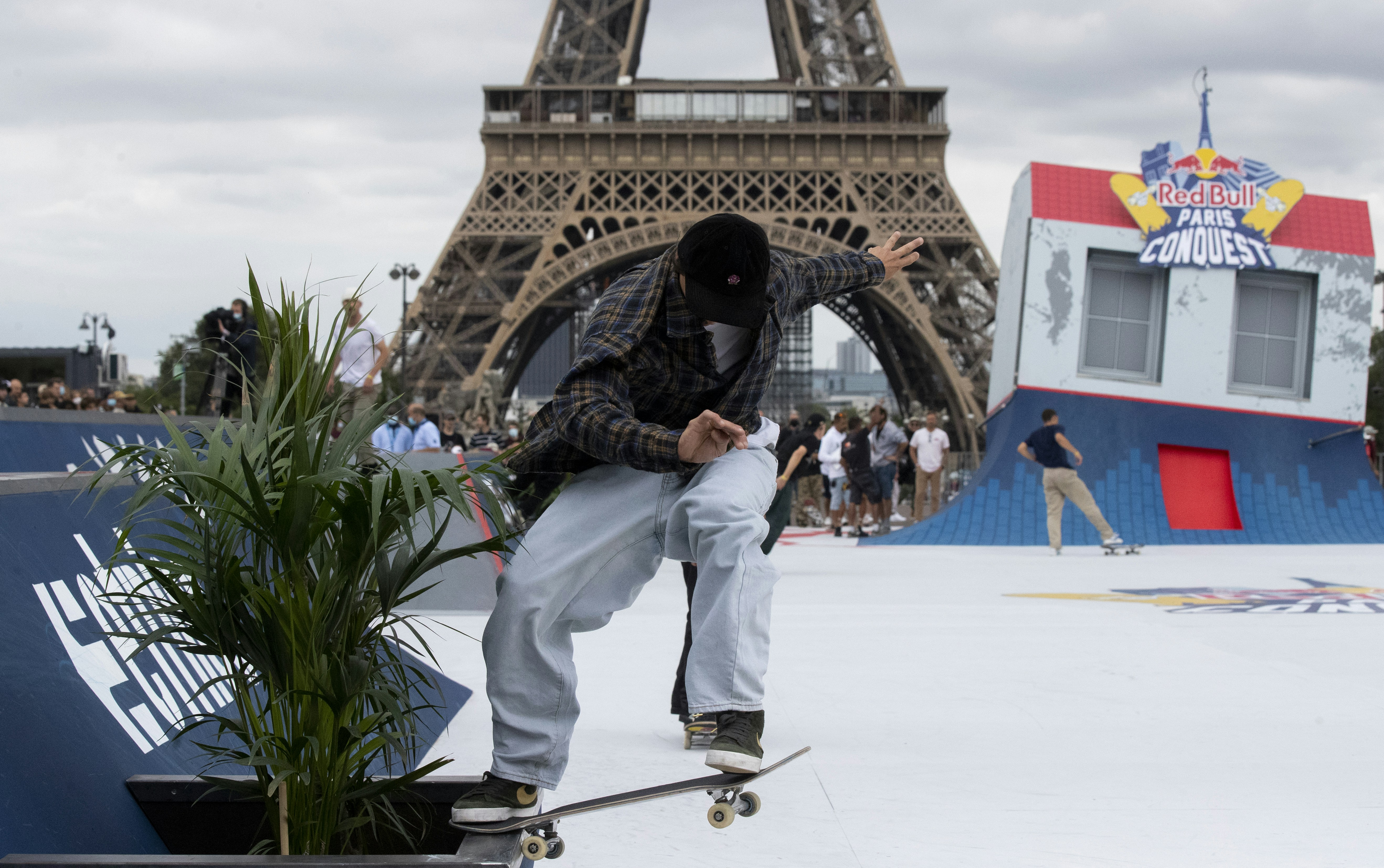 Skateboarder performing a trick in front of the iconic Eiffel Tower during a Red Bull event, showcasing the blend of sport and culture.