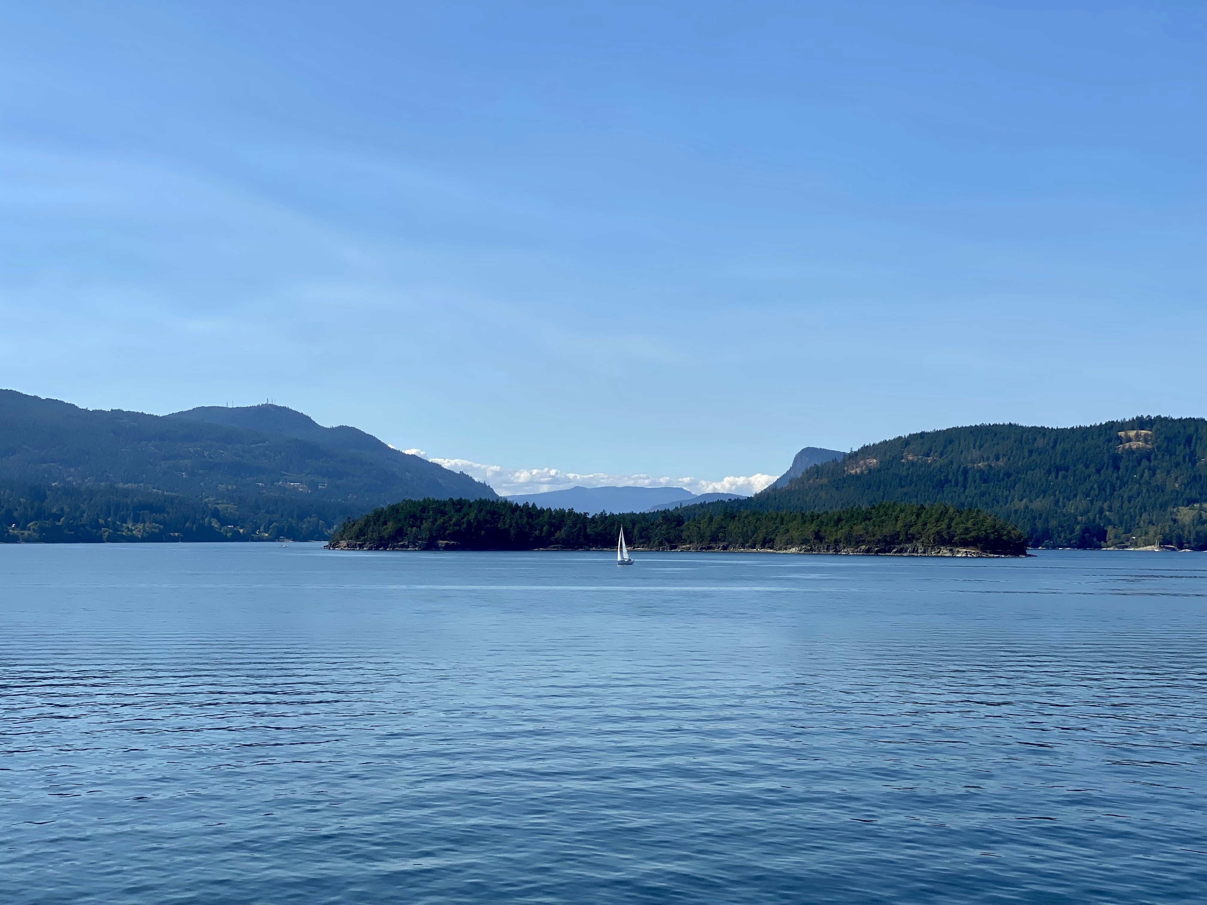 Calm blue waters stretch between forested islands under a clear sky.