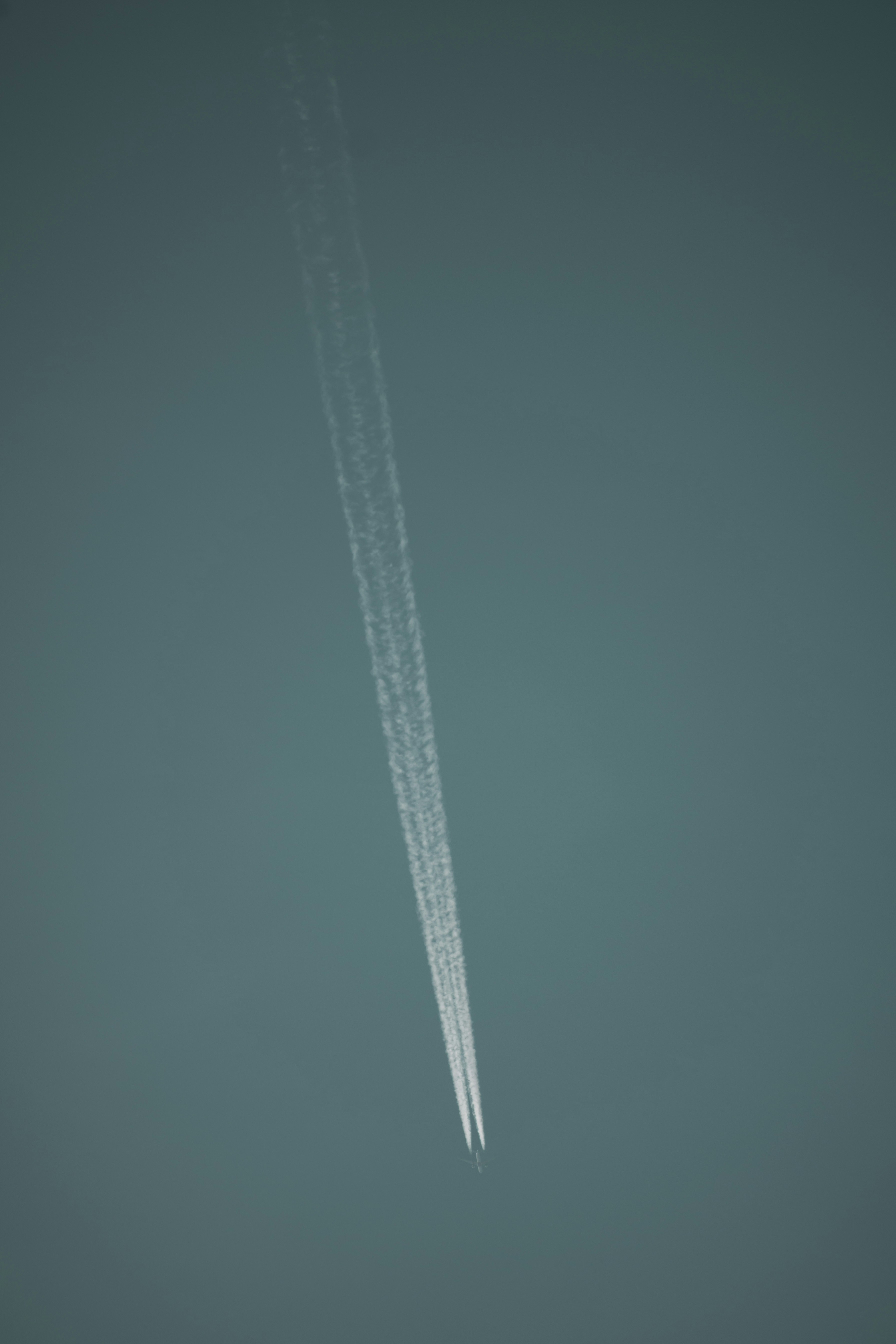 Contrail stretching across a muted sky, showcasing the fleeting passage of an aircraft high above. 
