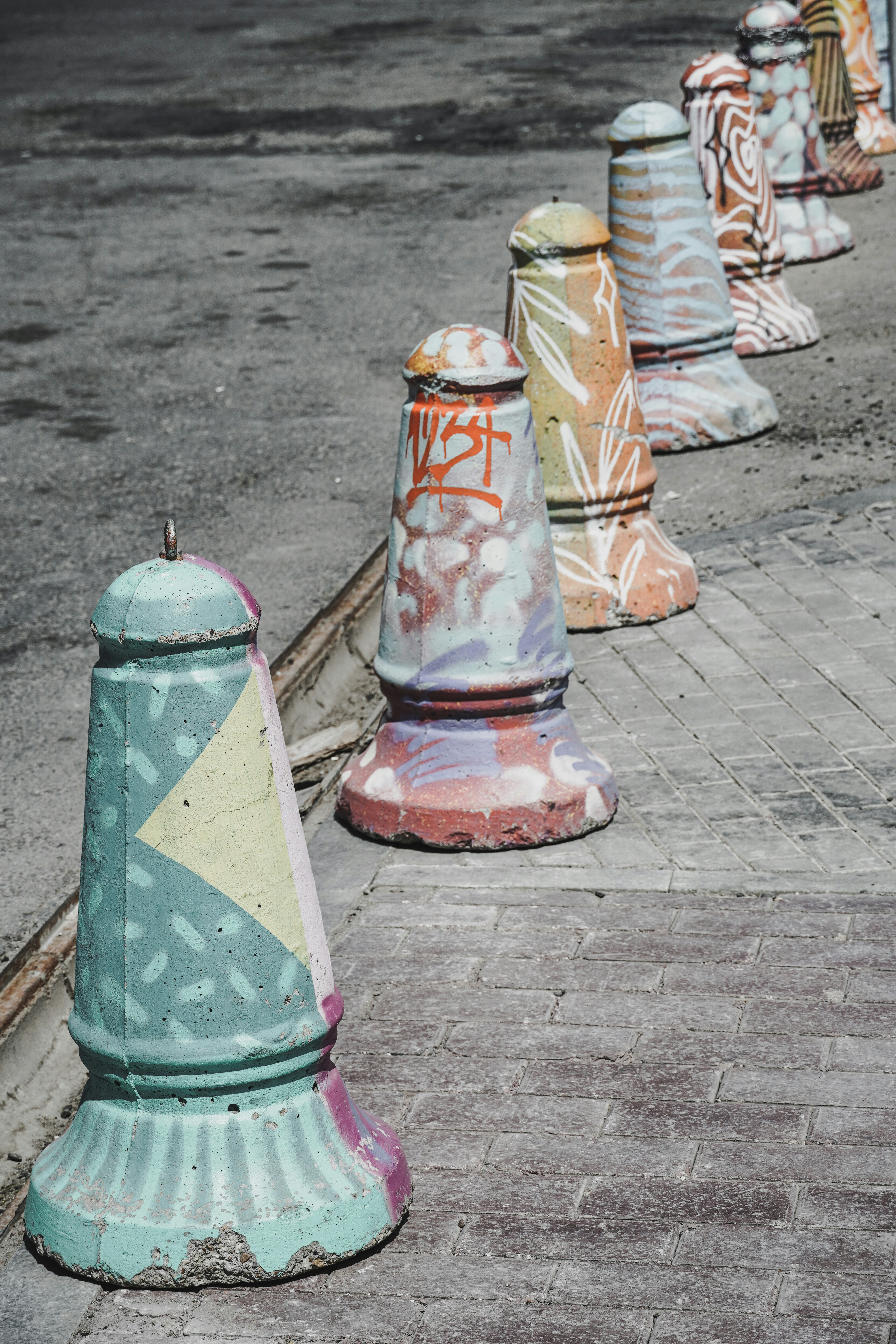 Pastel Sentinels: A Graffiti-Colored Row of Sidewalk Bollards