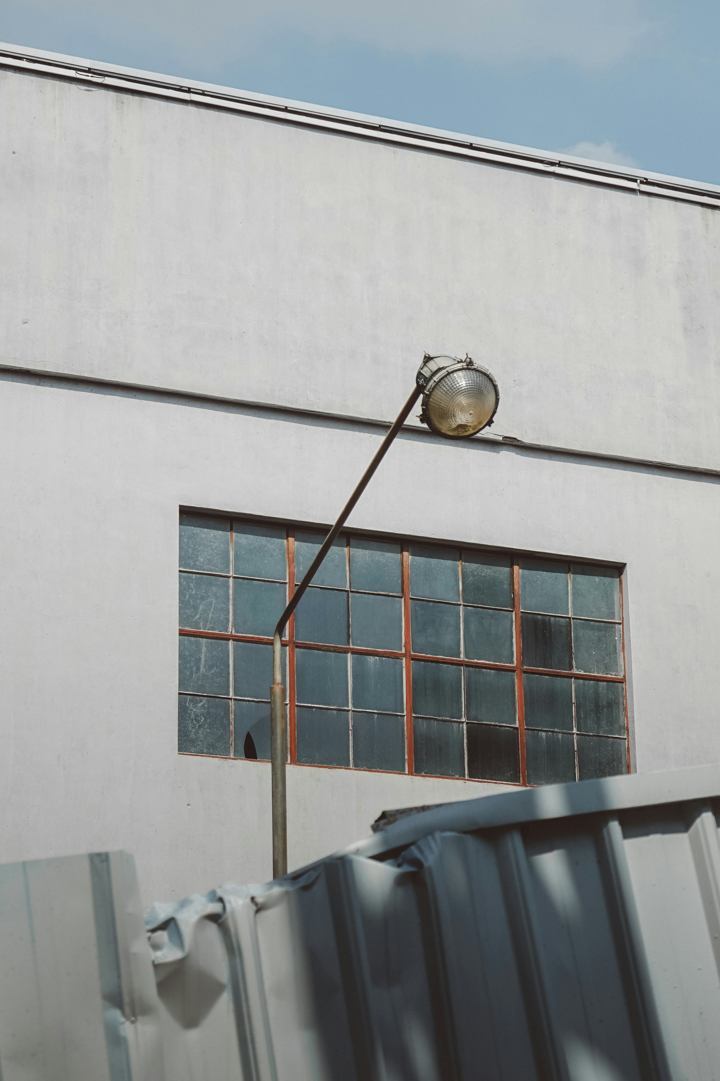 Rustic industrial wall with a vintage lamp and weathered window panes, reflecting the passage of time in an urban setting.