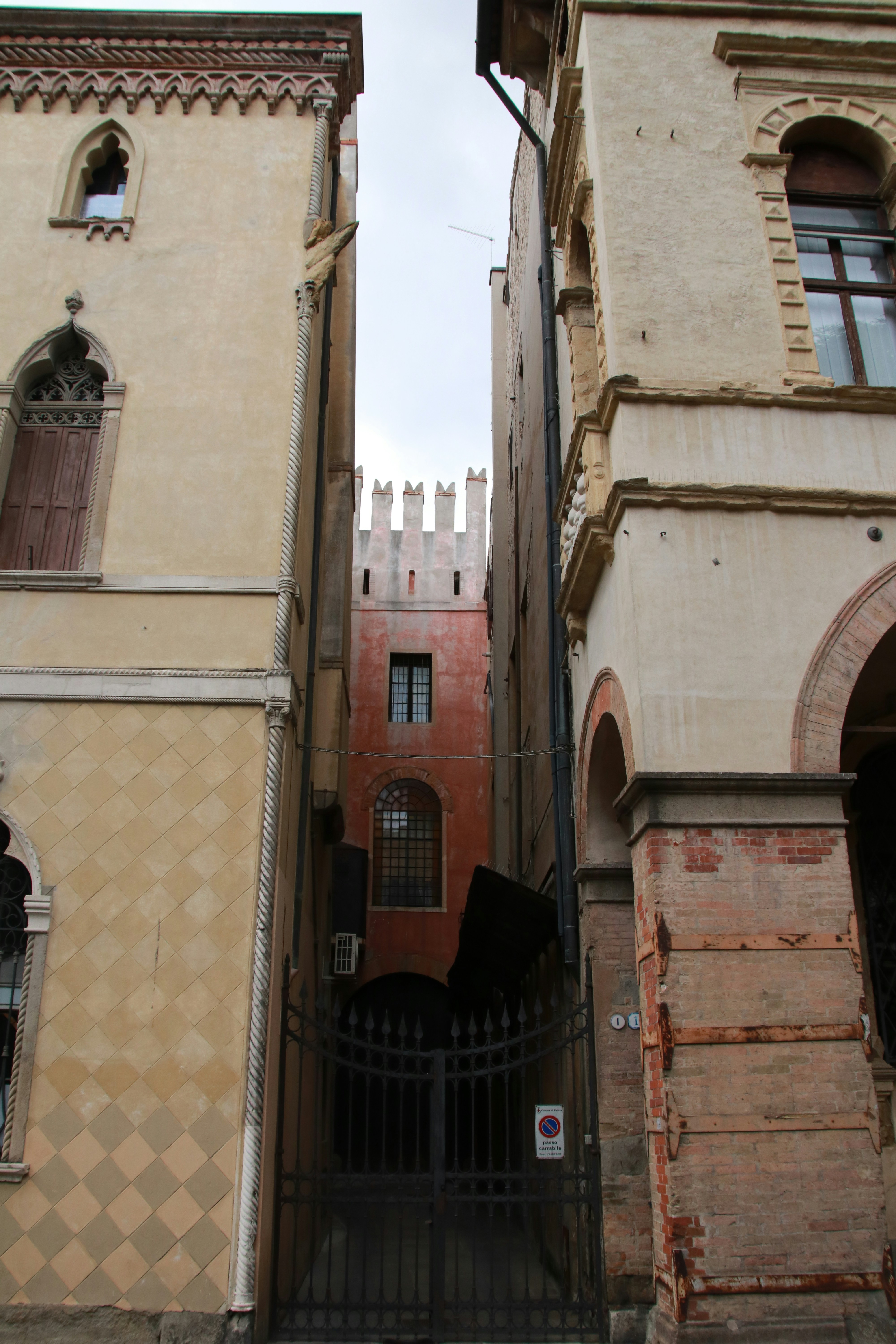 Between Weathered Facades, the Red-Crenellated Gate Emerges