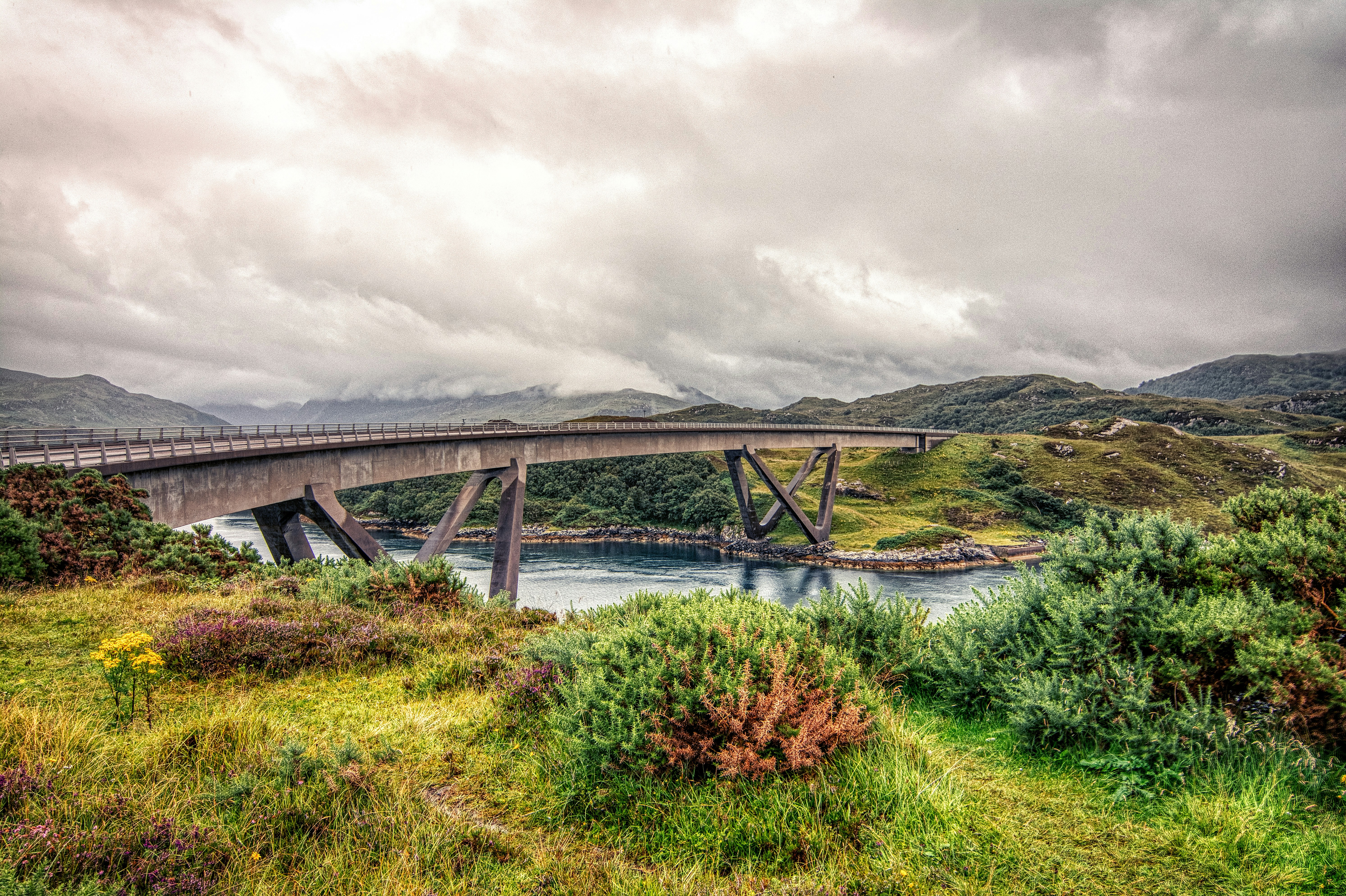 Bridge over Verdant Moor under a Moody Coastal Sky