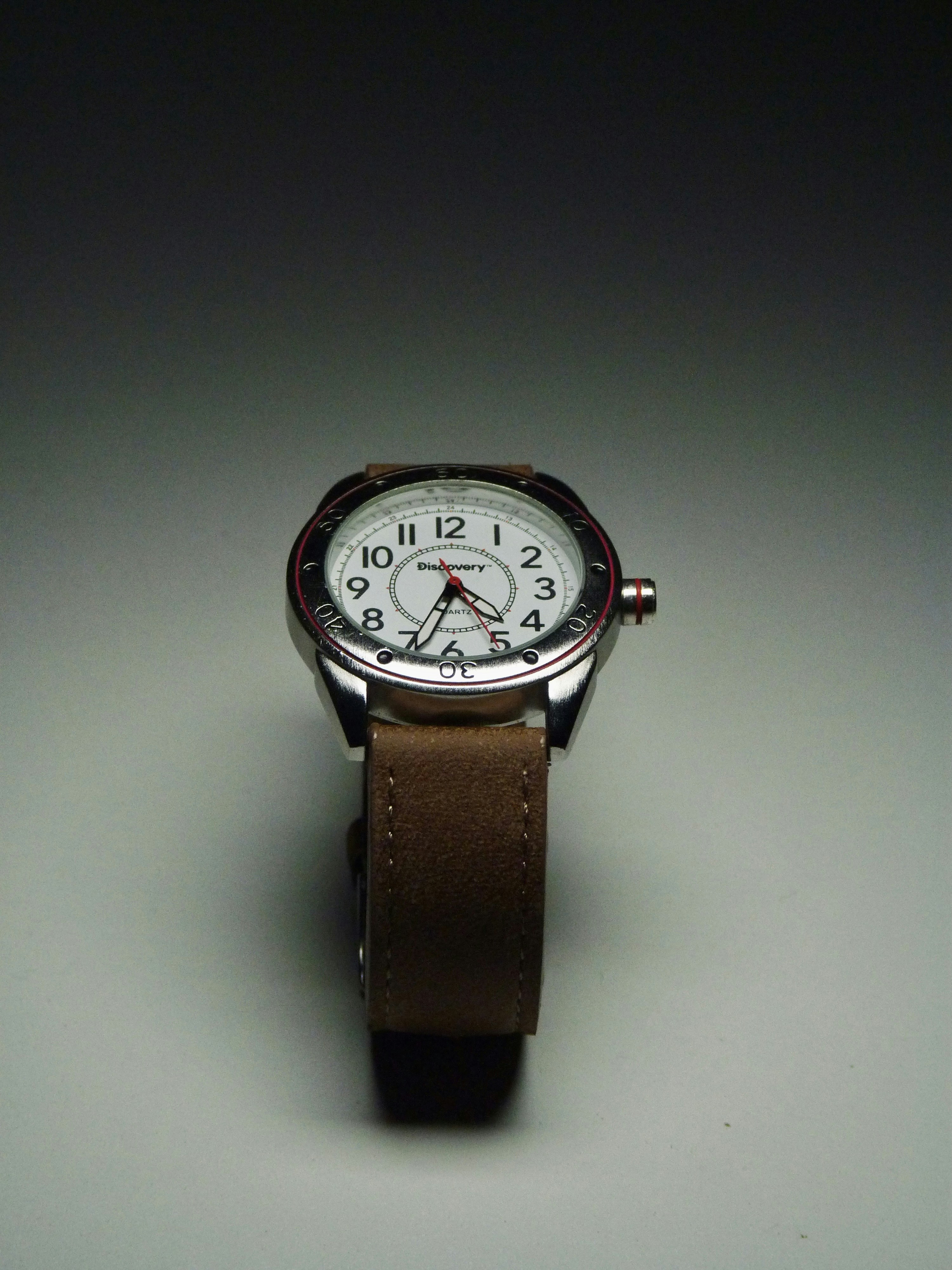 A stylish wristwatch featuring a white dial and brown leather strap, showcasing its intricate design and craftsmanship.