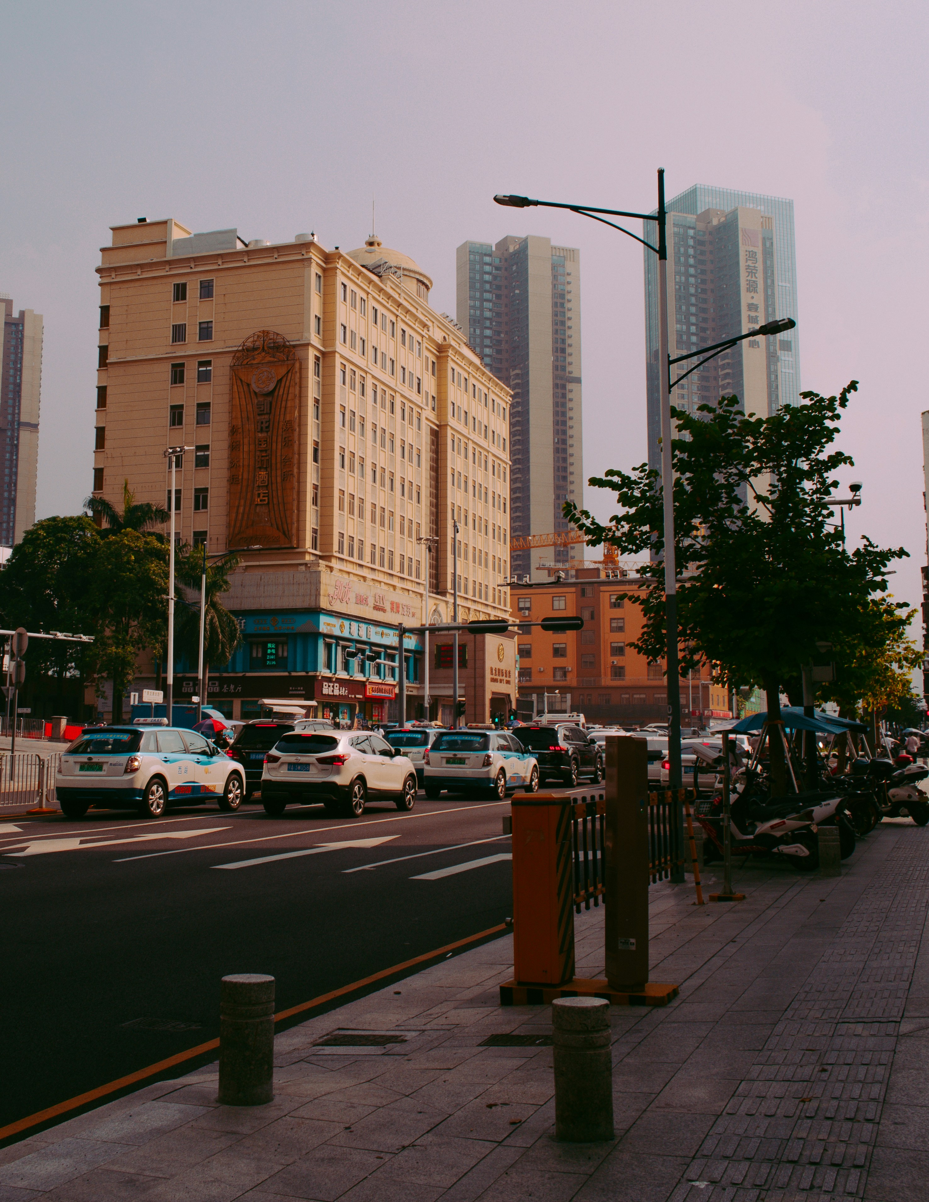 A historic building with intricate architecture stands amidst modern skyscrapers in a bustling city street, showcasing the blend of past and present.