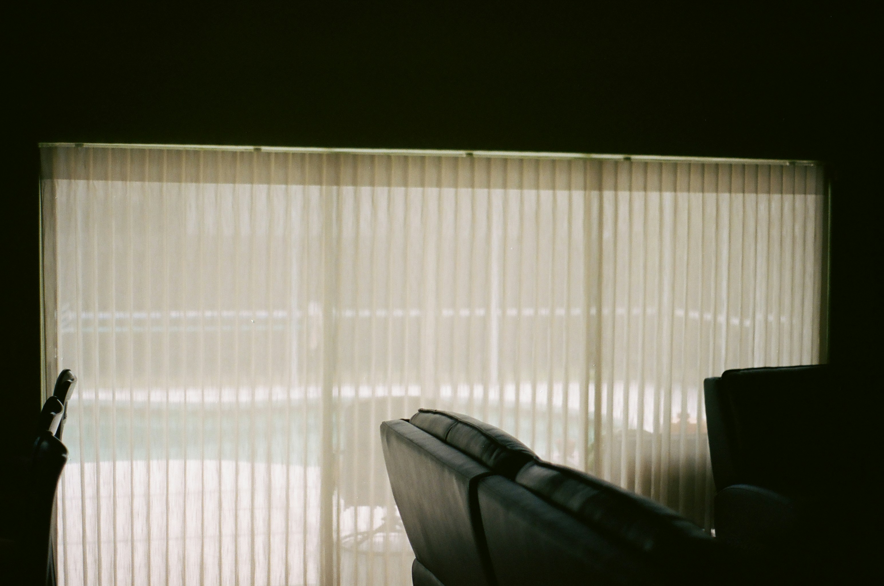 Light filters through sheer curtains, revealing silhouettes of furniture in a serene indoor setting.